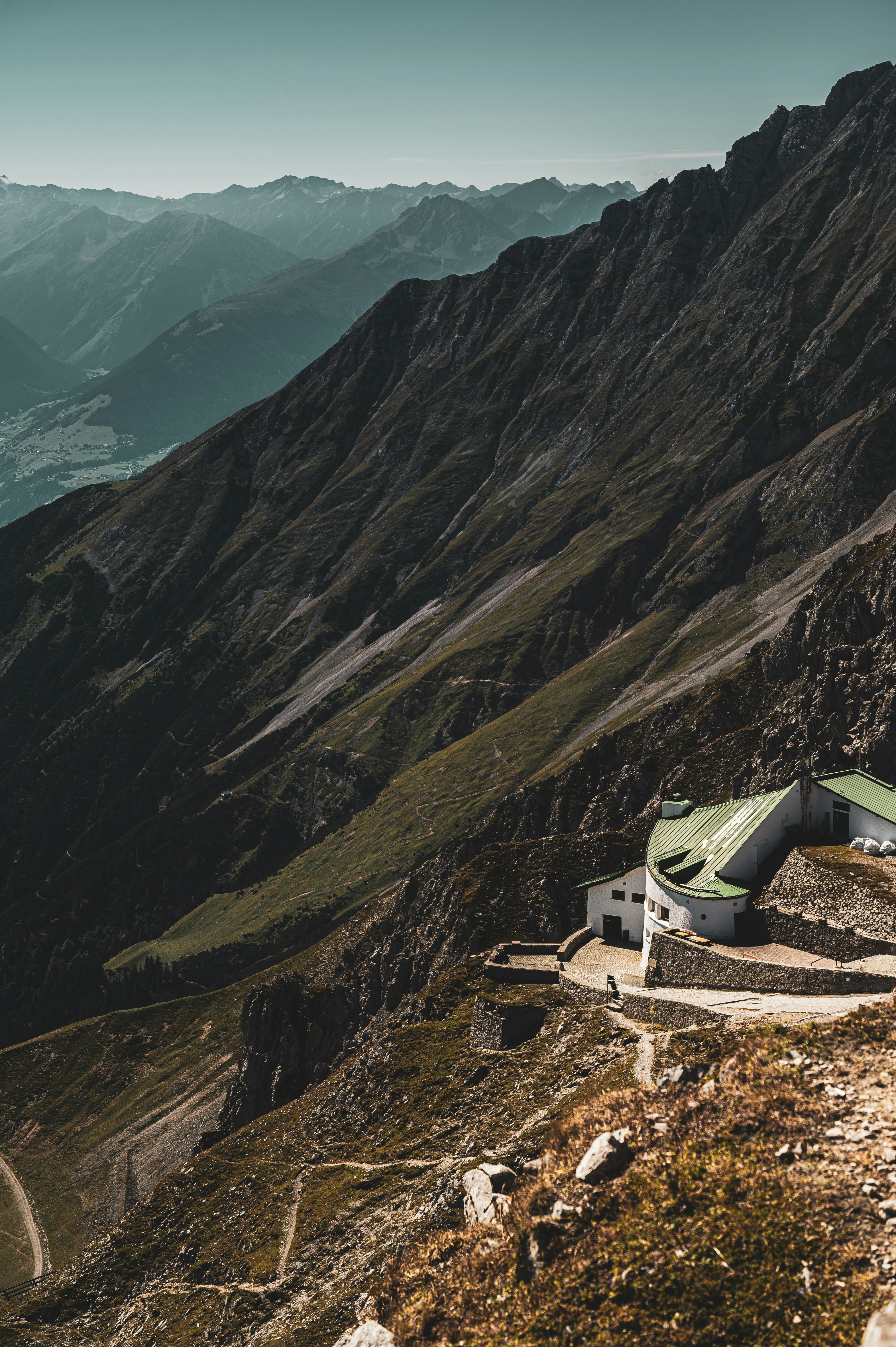 A house on the side of a mountain with mountains in the background