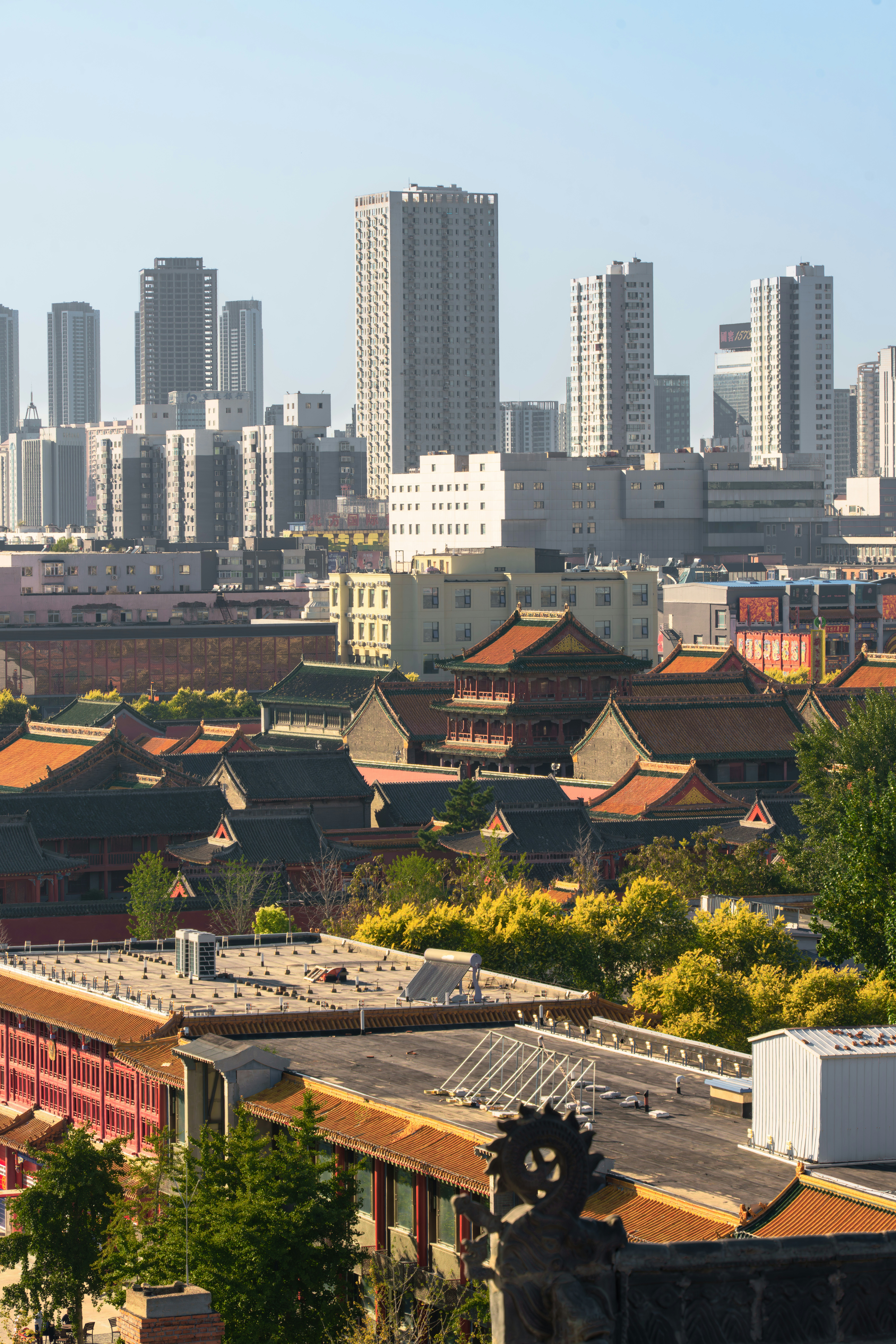 Historic rooftops of traditional architecture juxtaposed against a skyline of contemporary skyscrapers in a vibrant urban landscape.