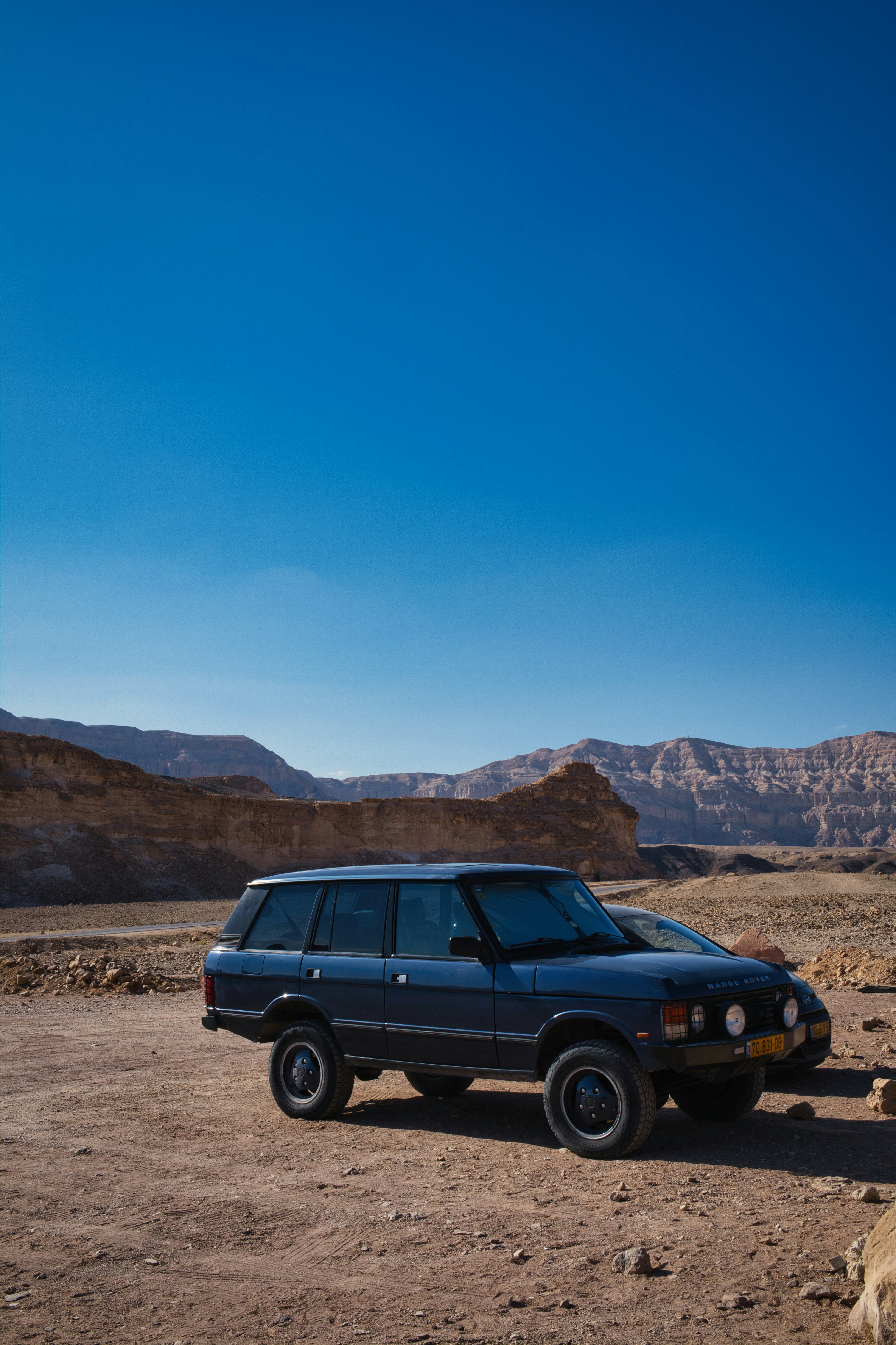 Blue Range Rover at the Desert Edge: A Quiet Presence Against Canyon Backdrop
