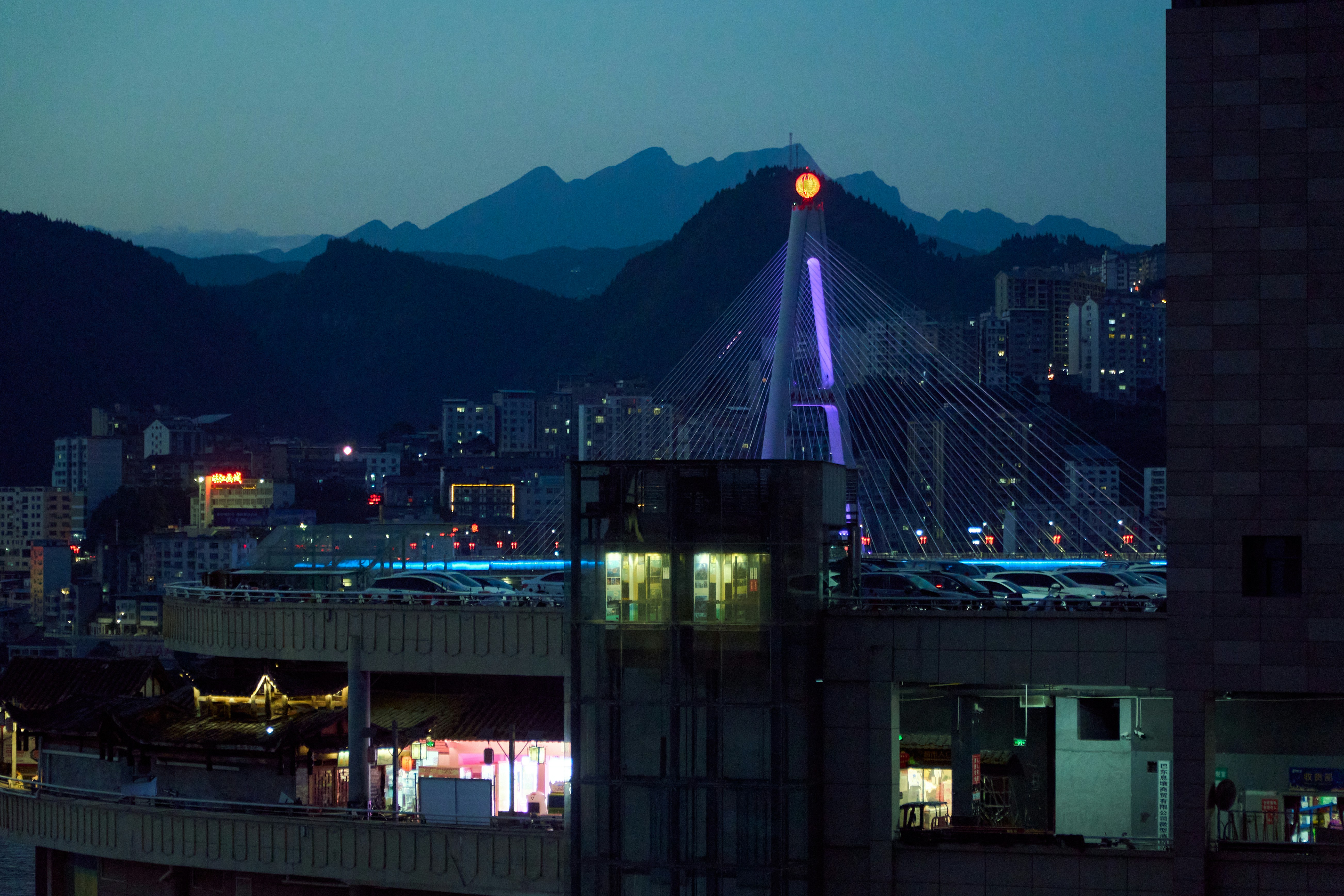 Night Cable Car Glow Over a Quiet Metro: City Silhouette Under Mountain Ridge