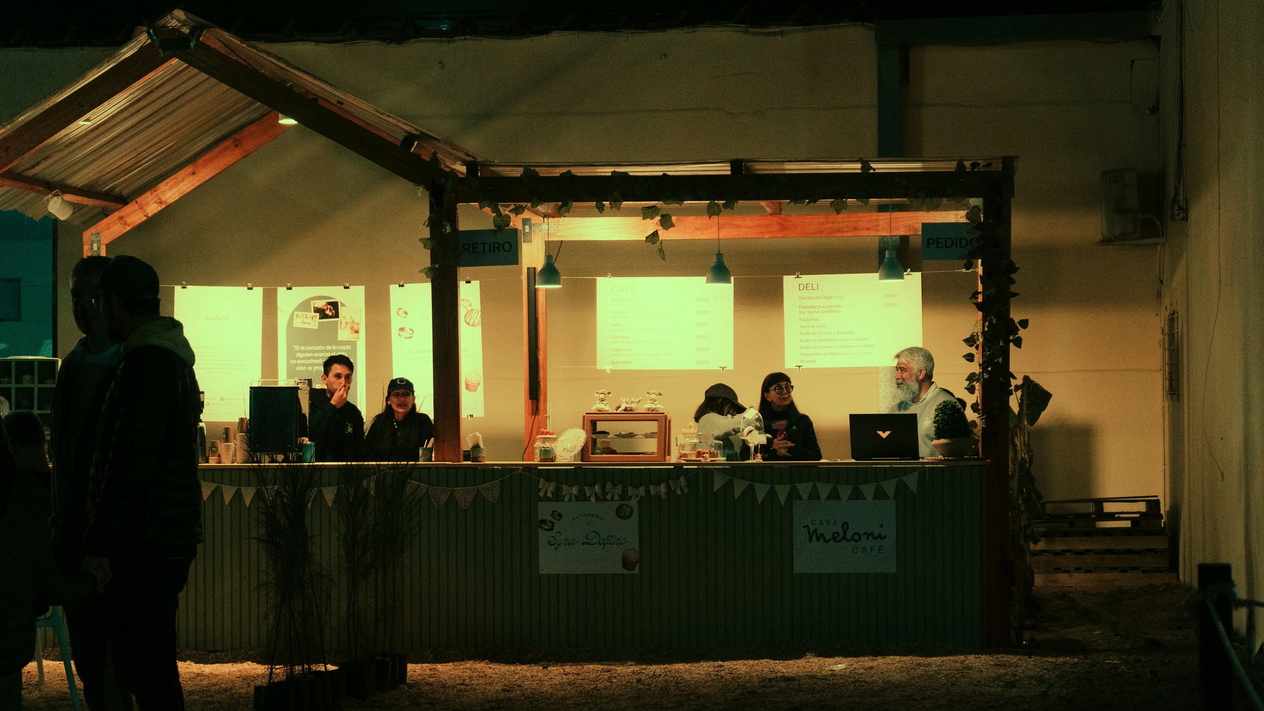 A community stand bustling with activity under soft lighting, showcasing a welcoming atmosphere with staff engaged in conversation and service.