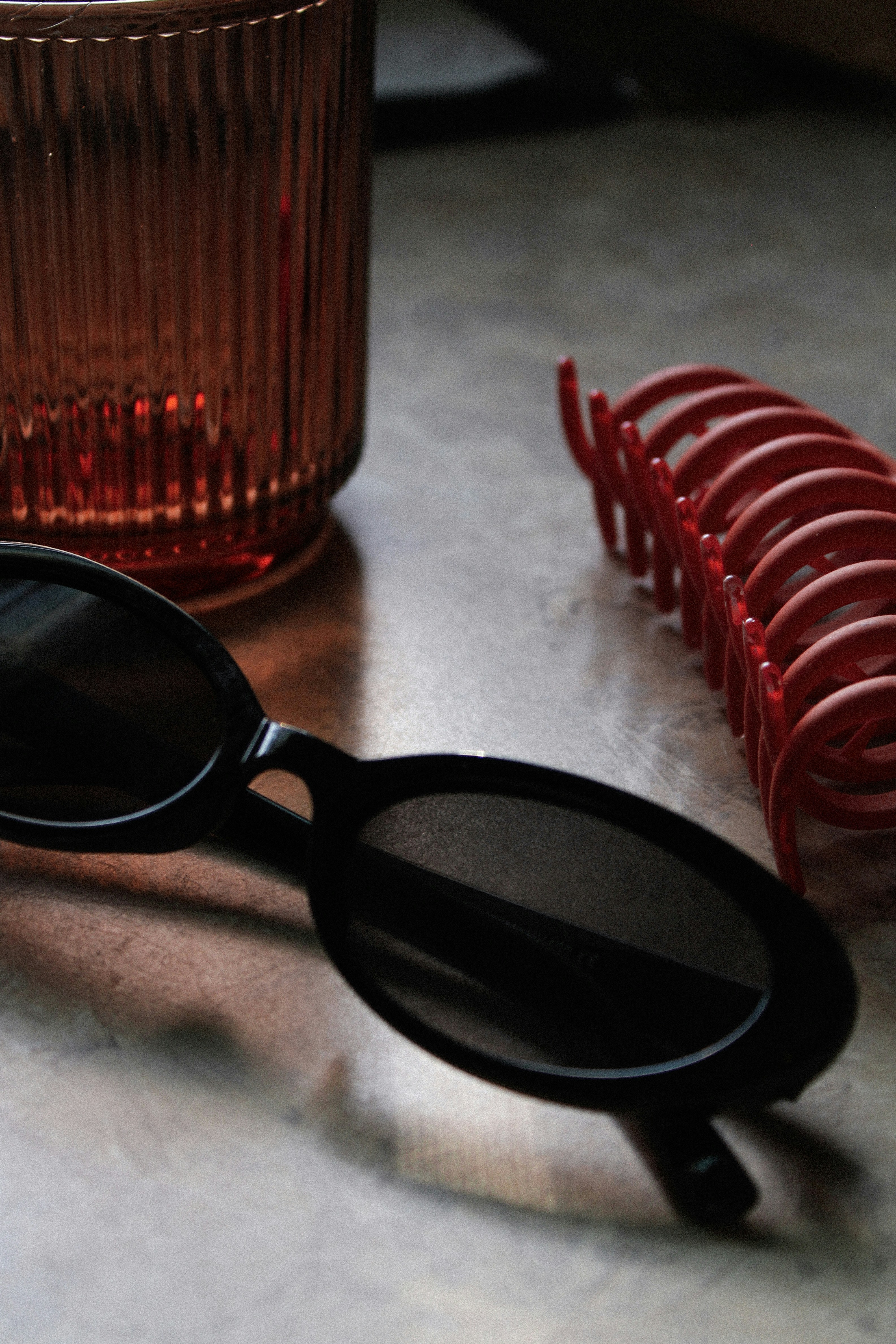 Crimson Glass, Coil, and Sunglasses: A Close-Up Still-Life on Brushed Metal