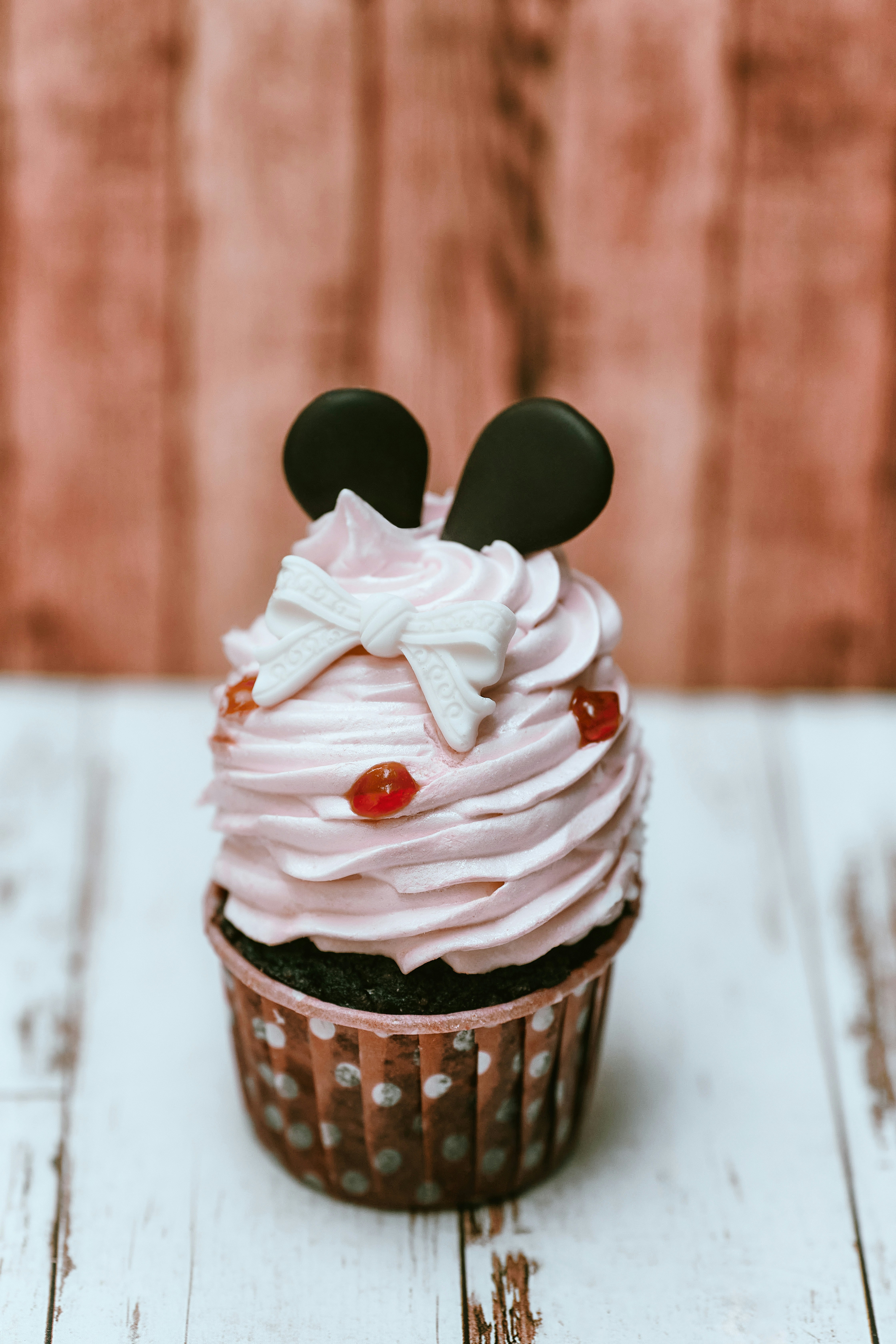 Minnie-Inspired Pink Cupcake Adorned with Bow and Ears on Rustic Wood