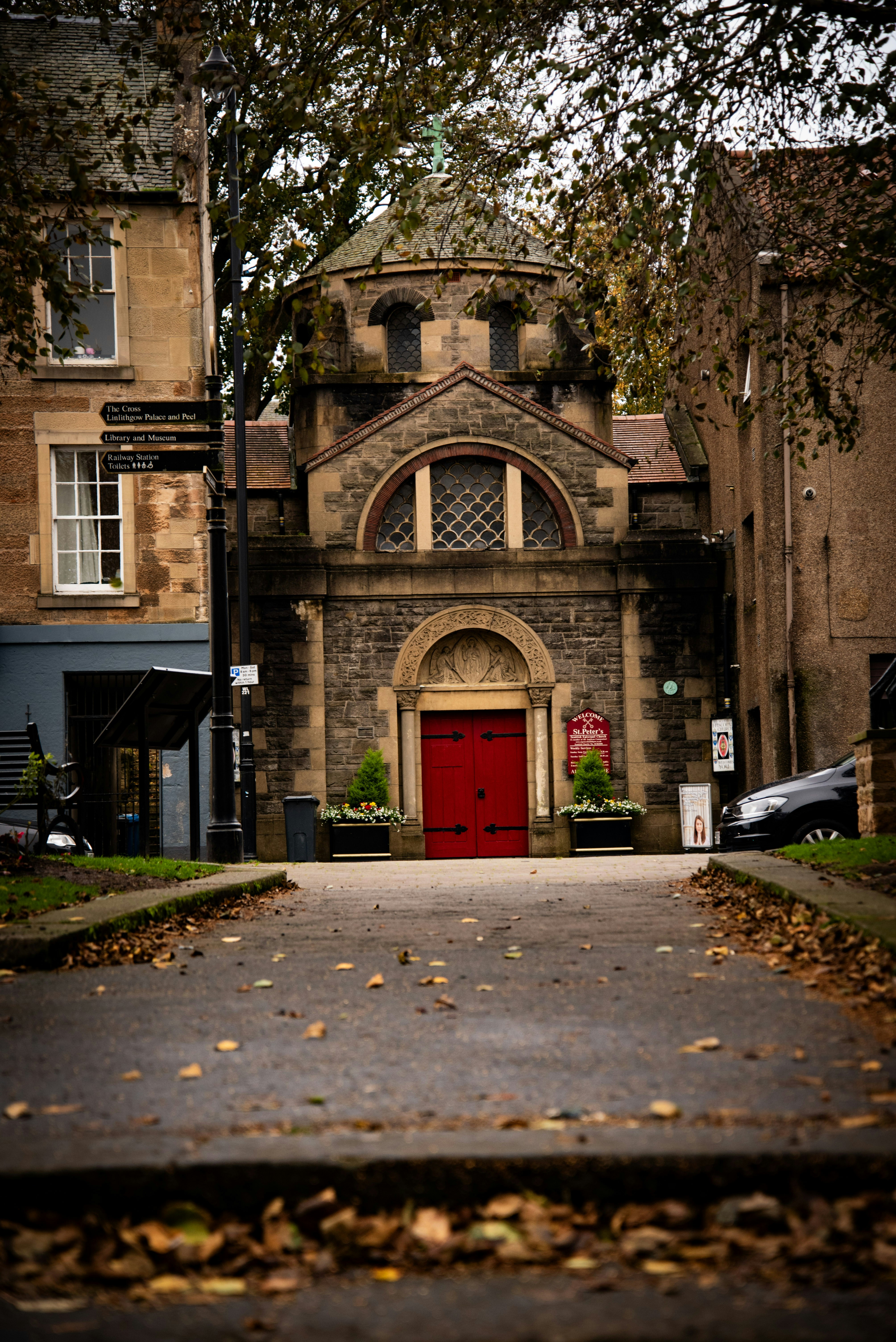 Red Door Cathedral: A Leaf-Littered Street Framed by Stone Facades