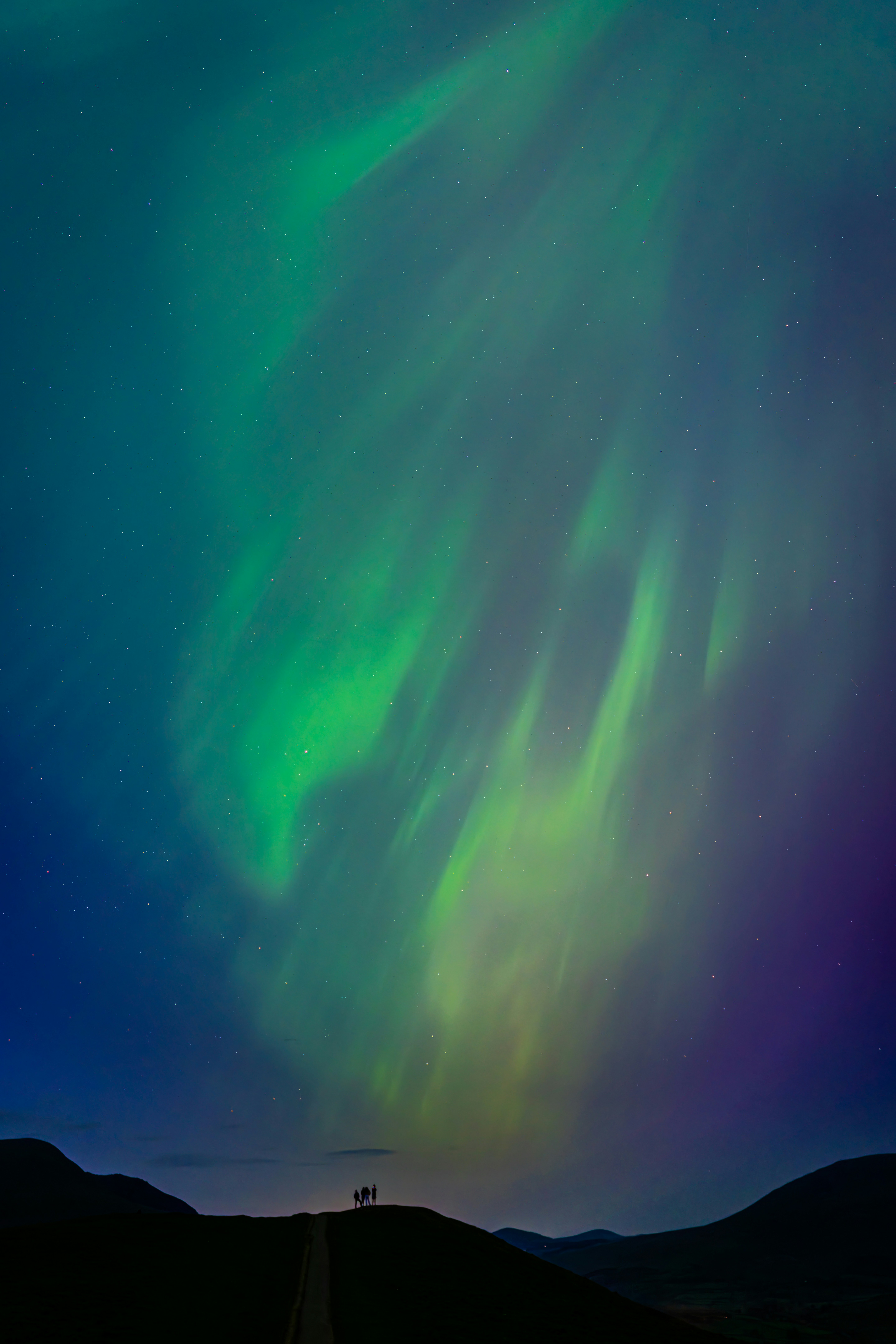 Um carro dirigindo por uma estrada sob um céu verde e azul foto ...