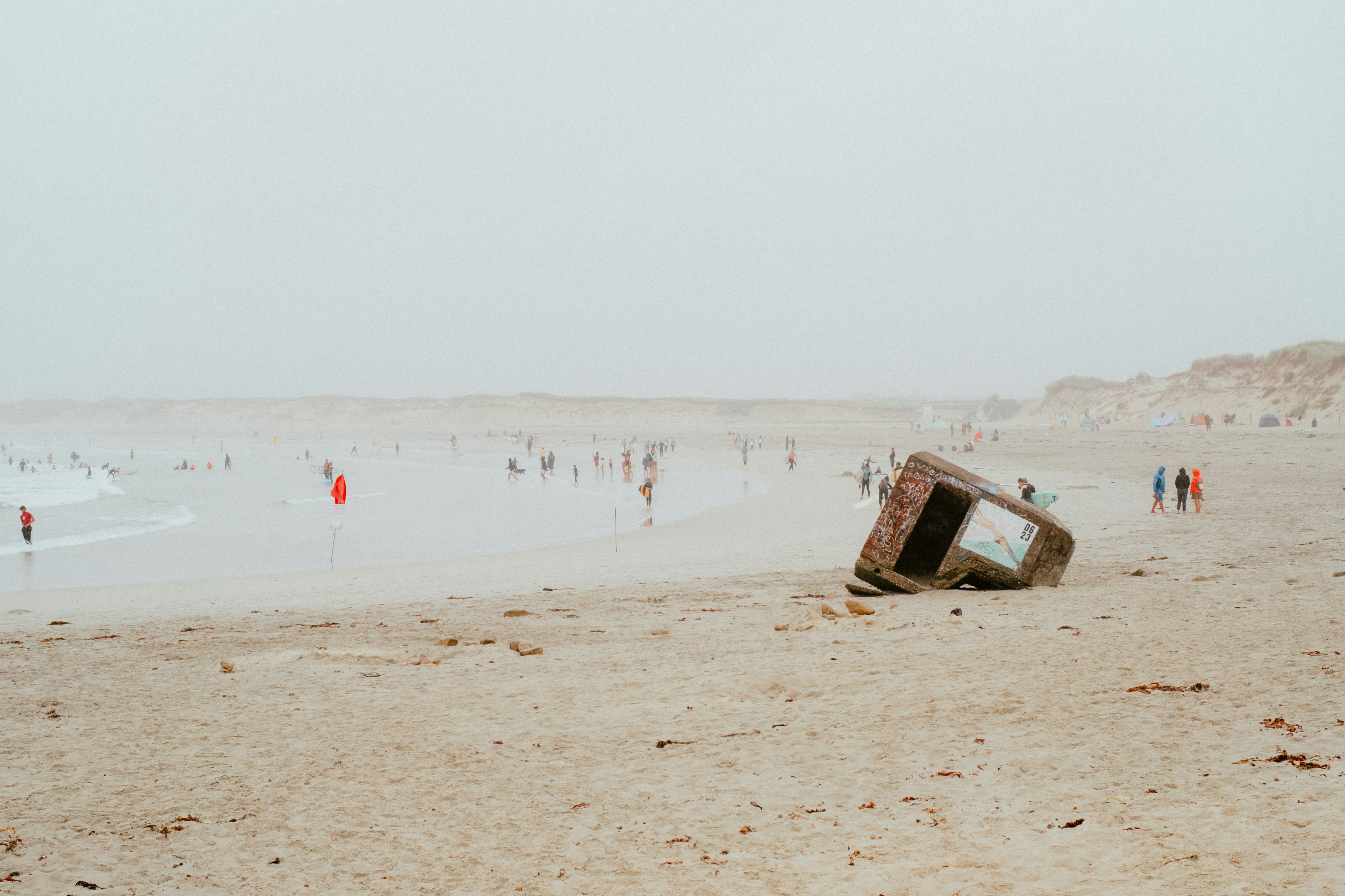 Rusted Broadcast on the Dunes: A TV Lies Aground Amid Mist and Tide