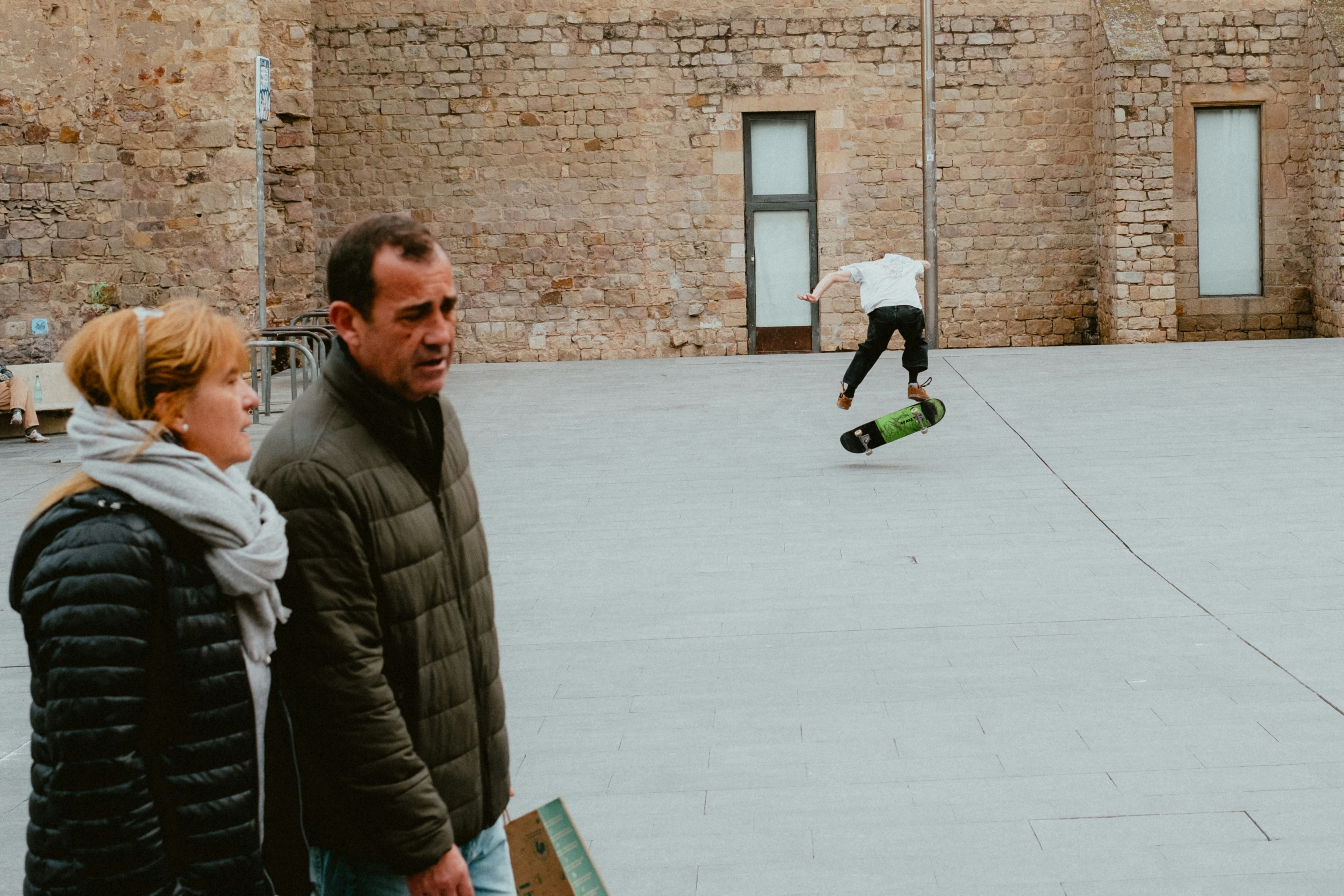 Onlookers and a distant skater: a quiet courtyard moment