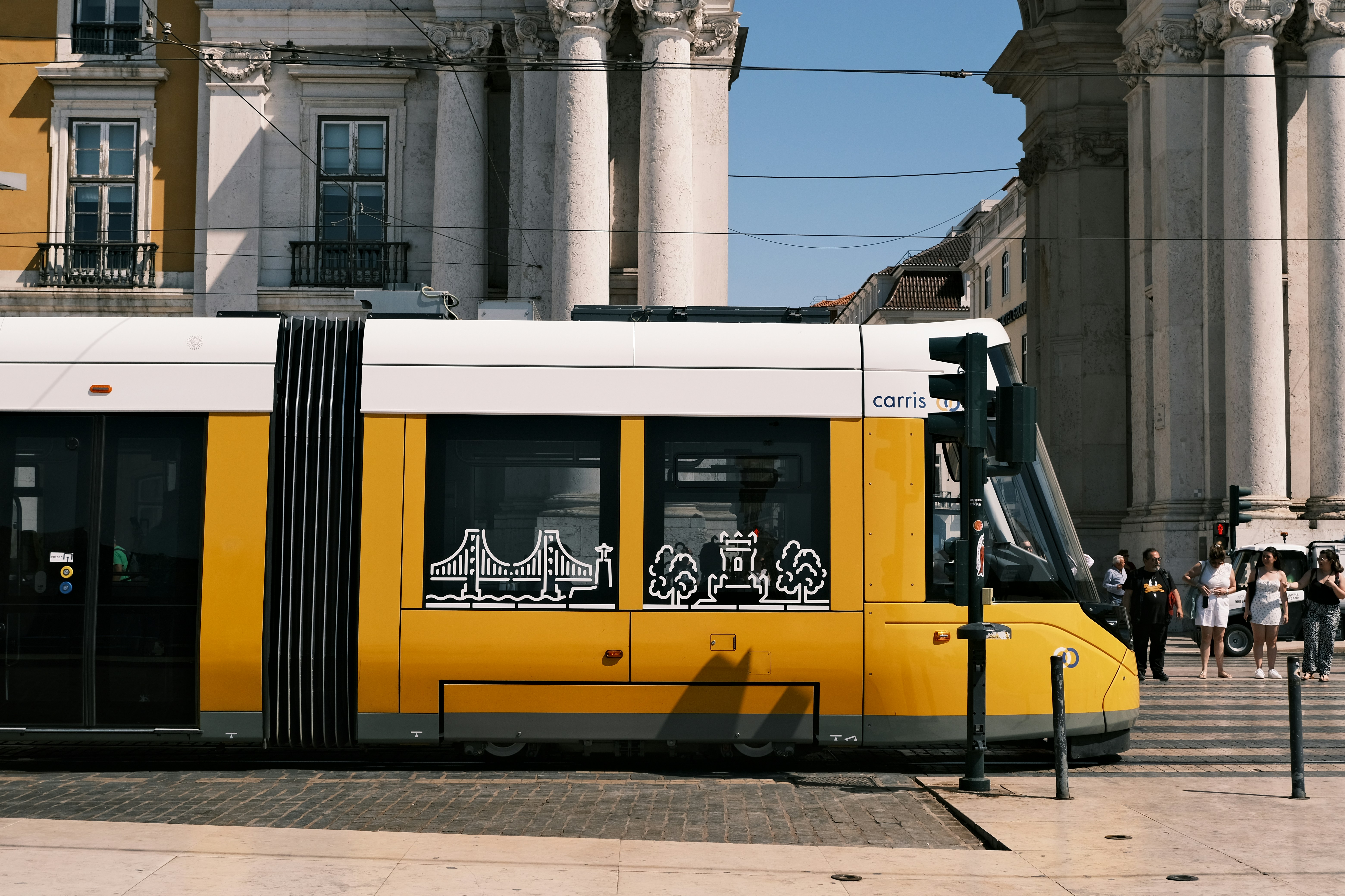 Golden Tram Against a Marble-Arcade Backdrop: City Pulse on a Sunny Plaza