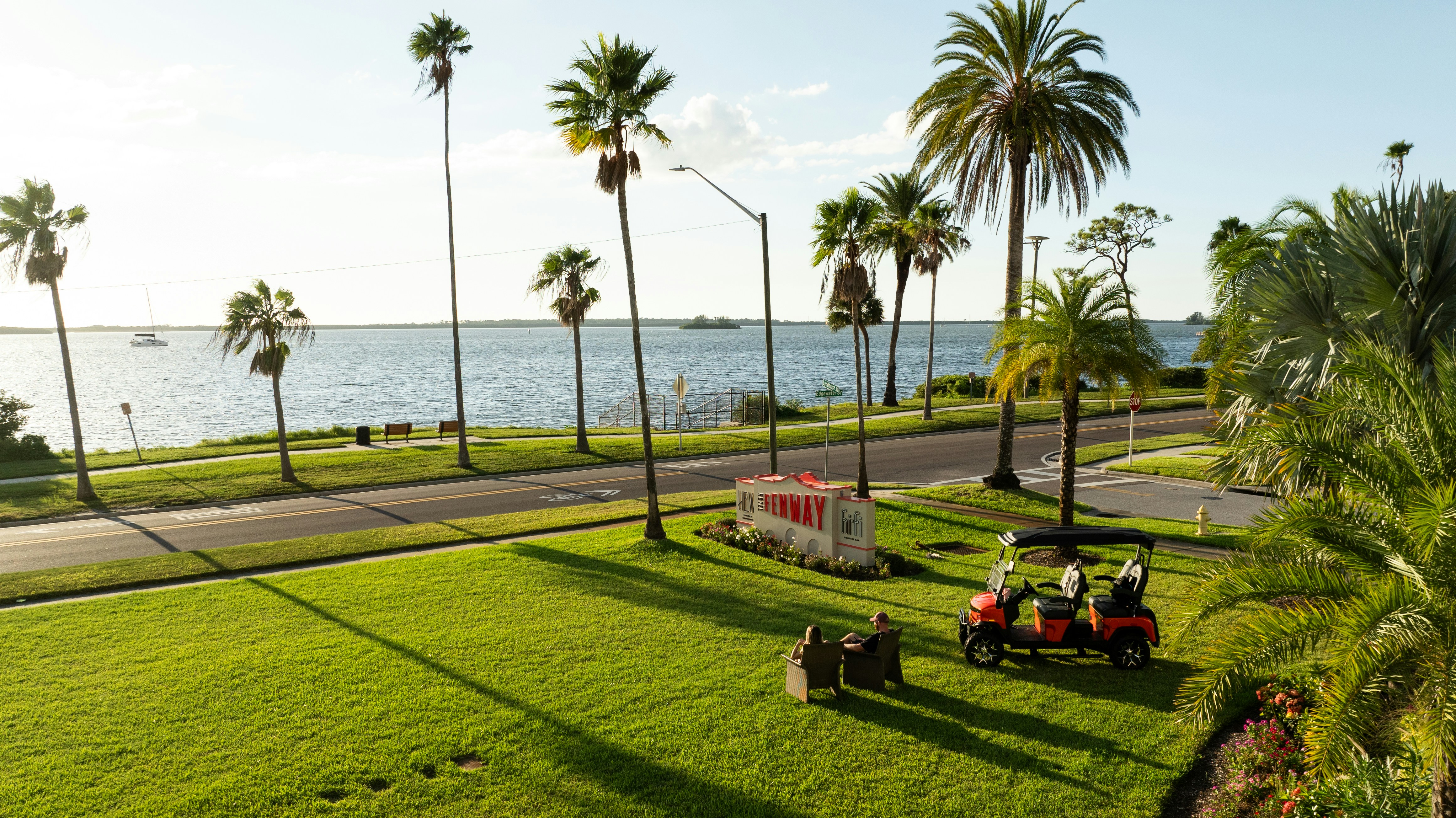 Palm-Lined Seafront Lawn with a Red Golf Cart