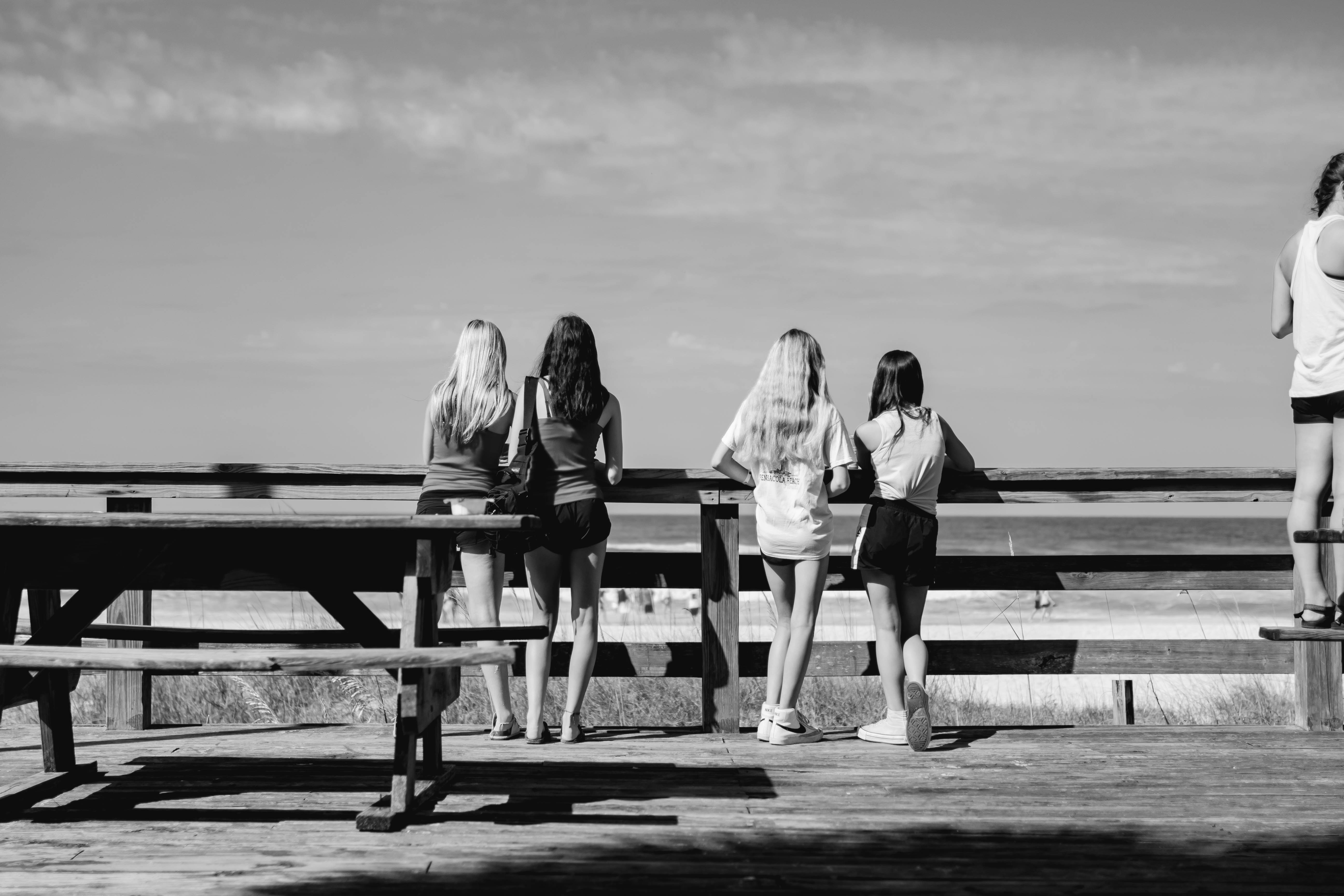Five Silhouettes Along the Boardwalk Meet the Distant Horizon