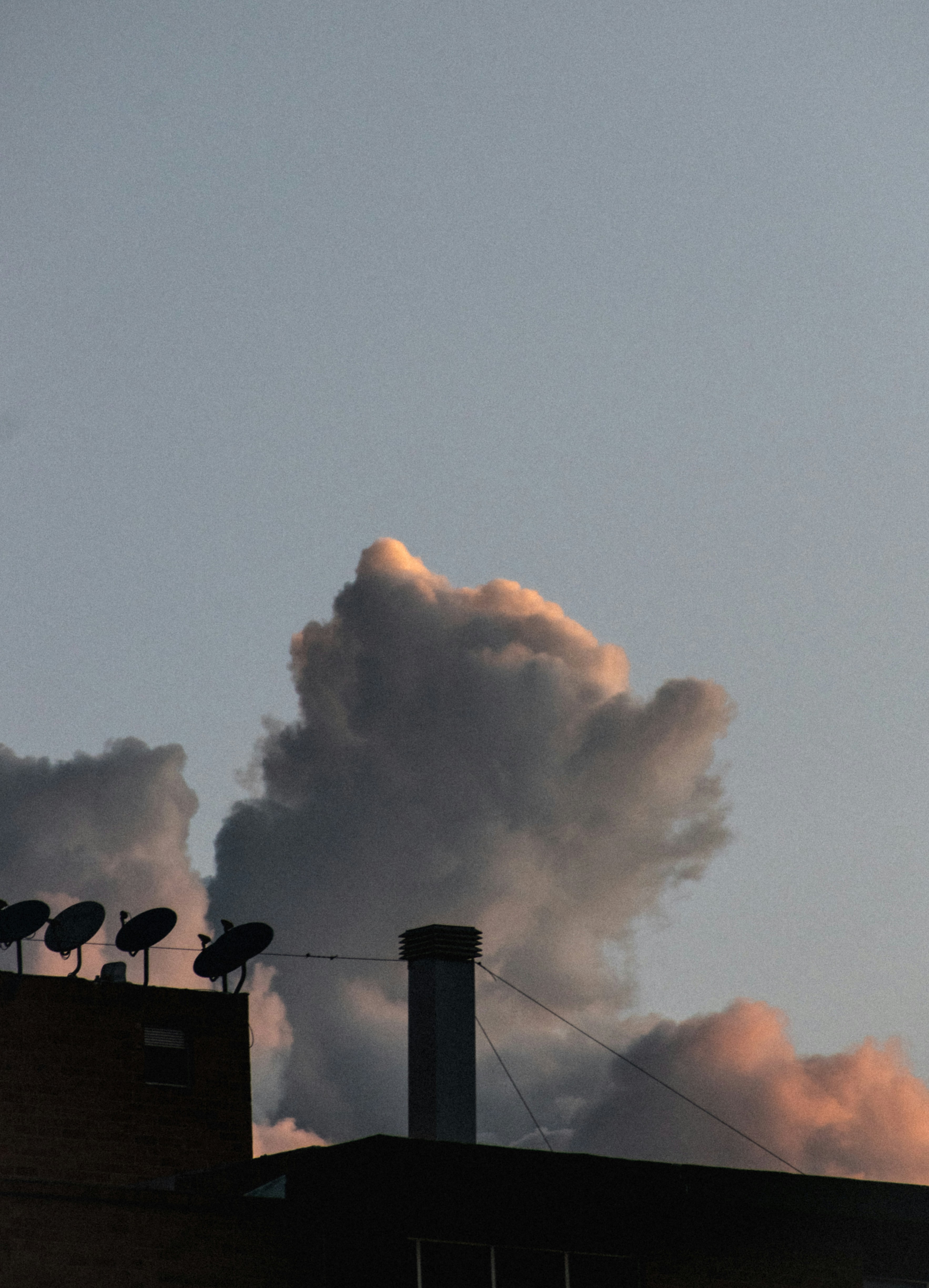 Cumulus Crown Over an Urban Rooftop: Dishes, Chimney, and a Golden Sky