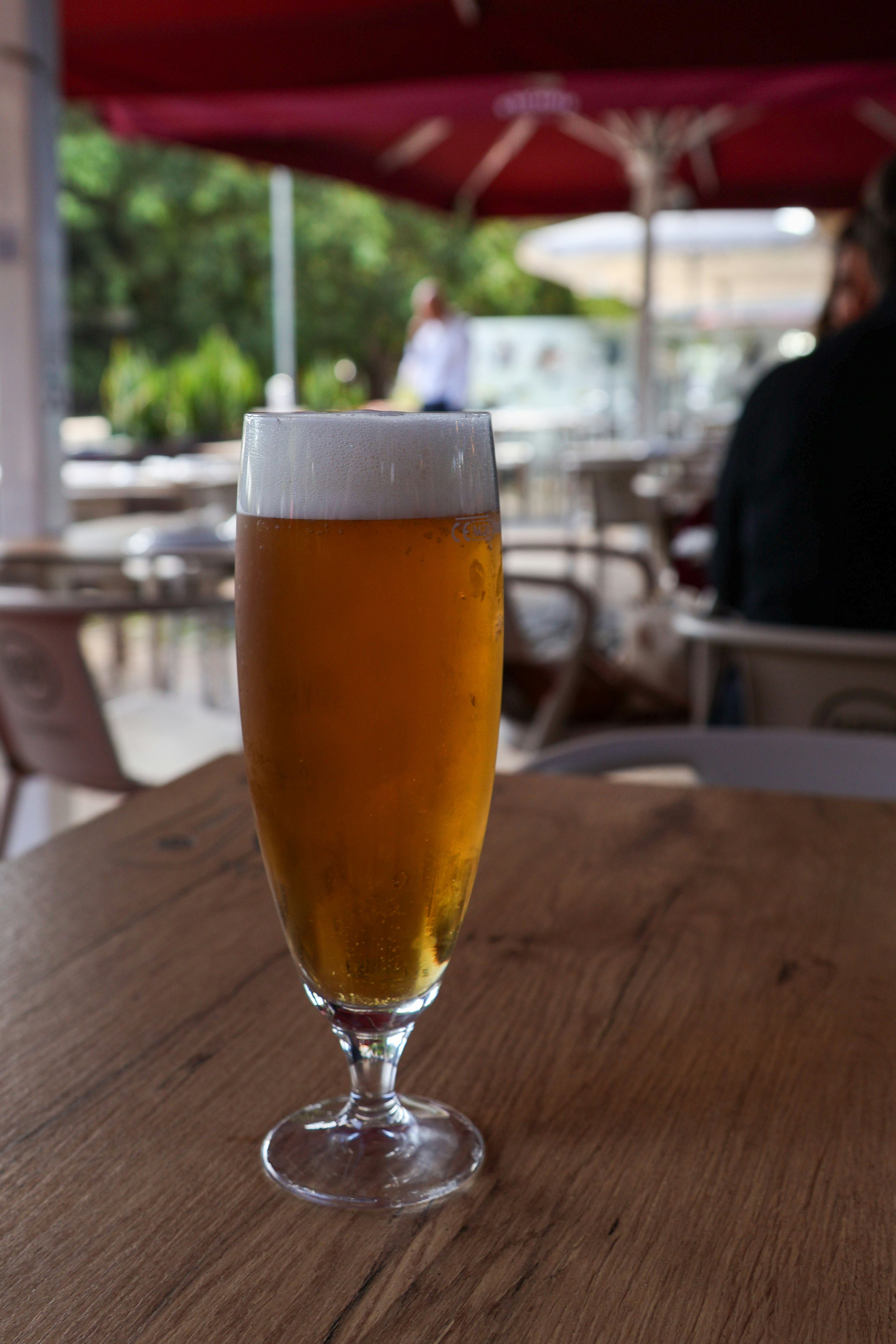 Amber Toast on a Sunlit Patio: A Beer Glass in Soft Outdoor Blur