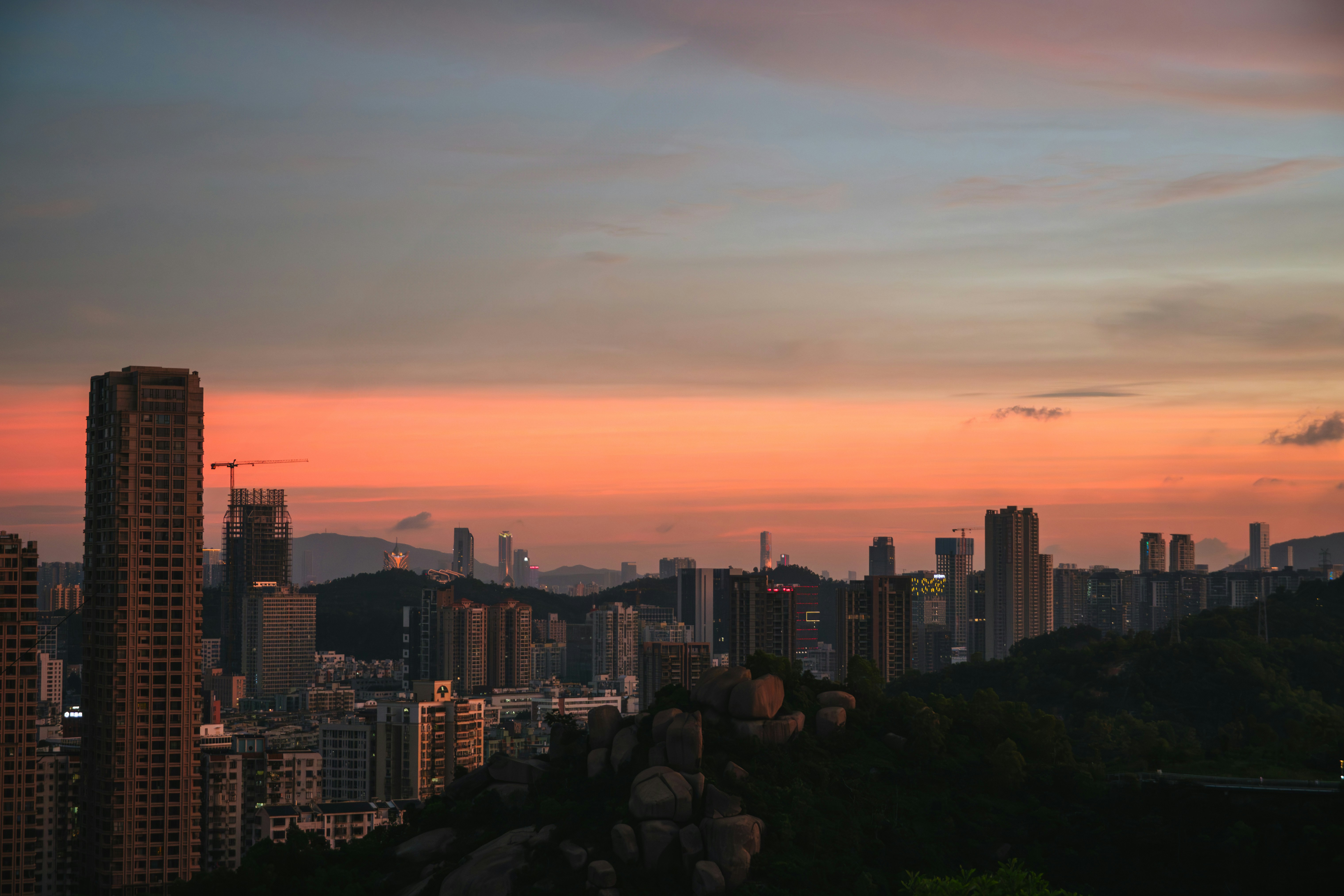 City skyline at dusk, featuring high-rise buildings silhouetted against a vibrant sunset sky.