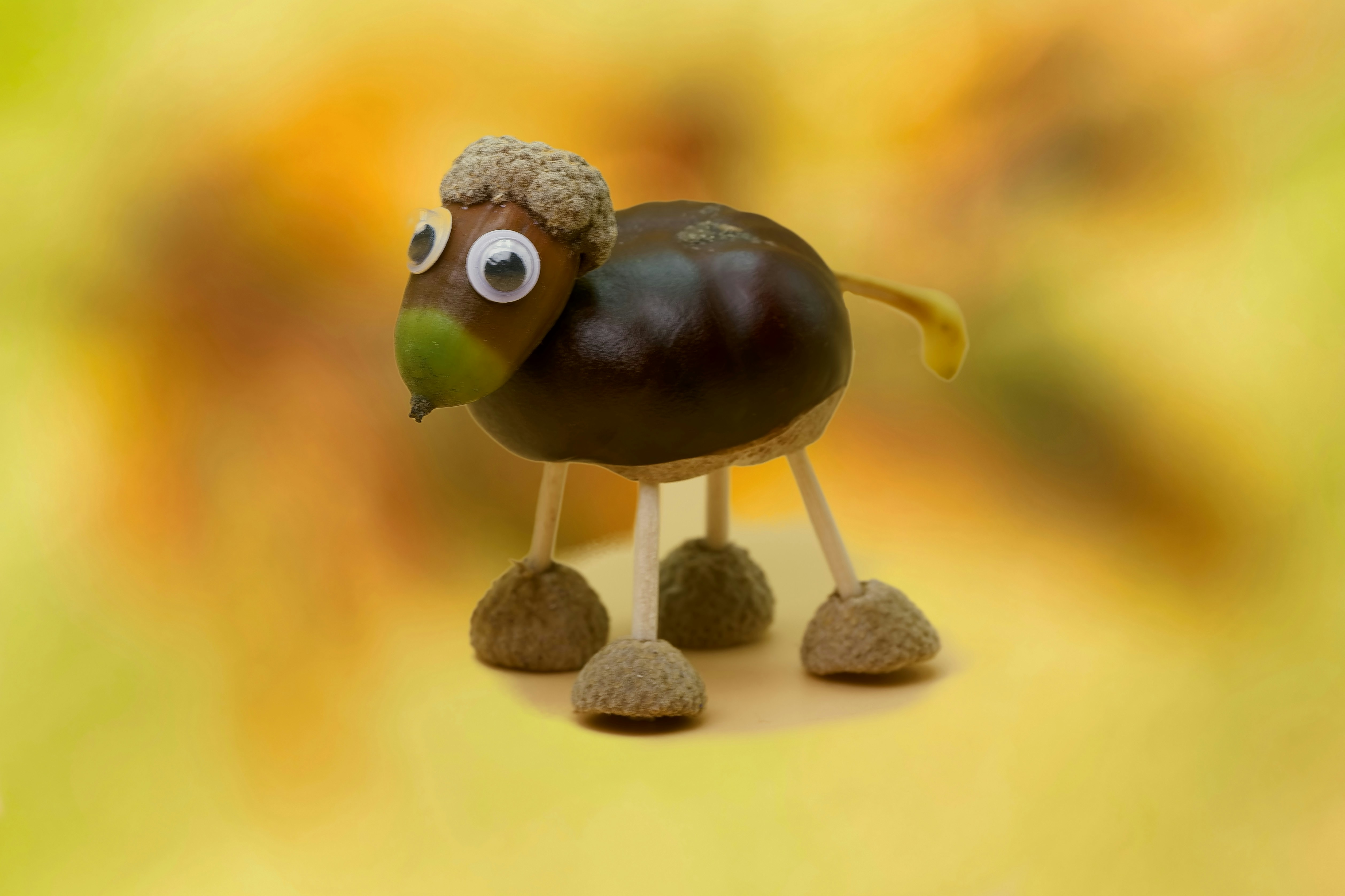 Close-up of a handmade clay sheep with googly eyes, set against a warm, golden-bokeh background. The focus highlights the playful craftsmanship and the subject's charm.