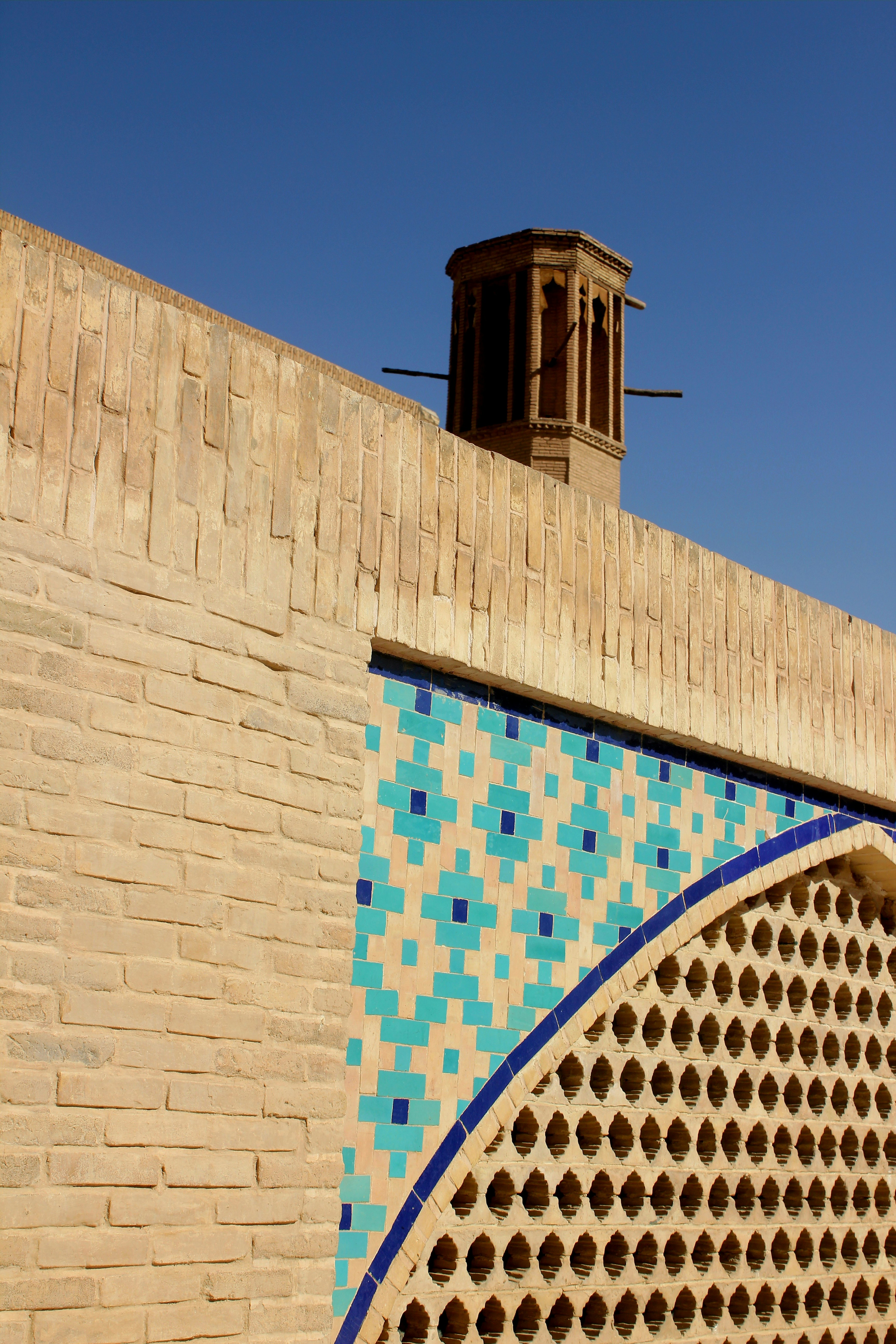 Chimney Over Mosaic Arch: A Sunlit Brick Facade
