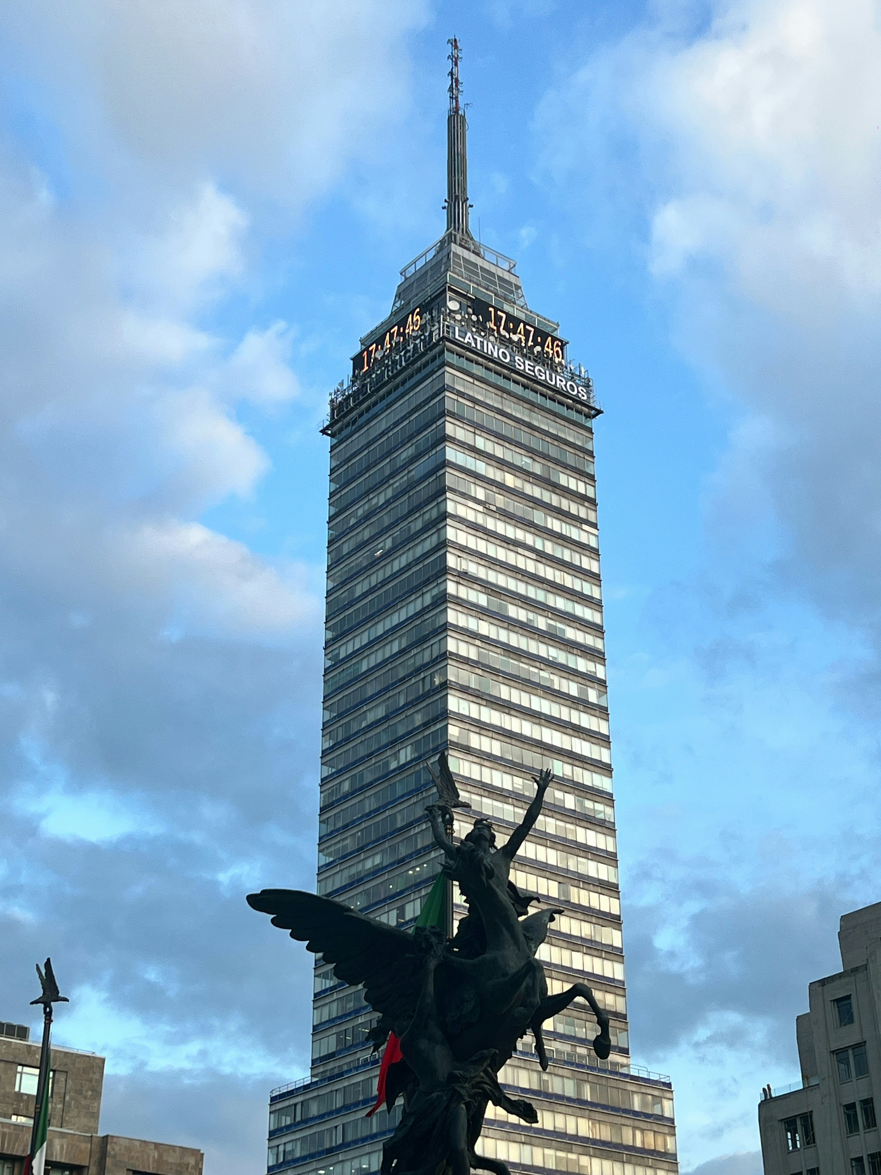 Cerulean Skies Over a Tapered Tower, Framed by a Bronze Pegasus Monument
