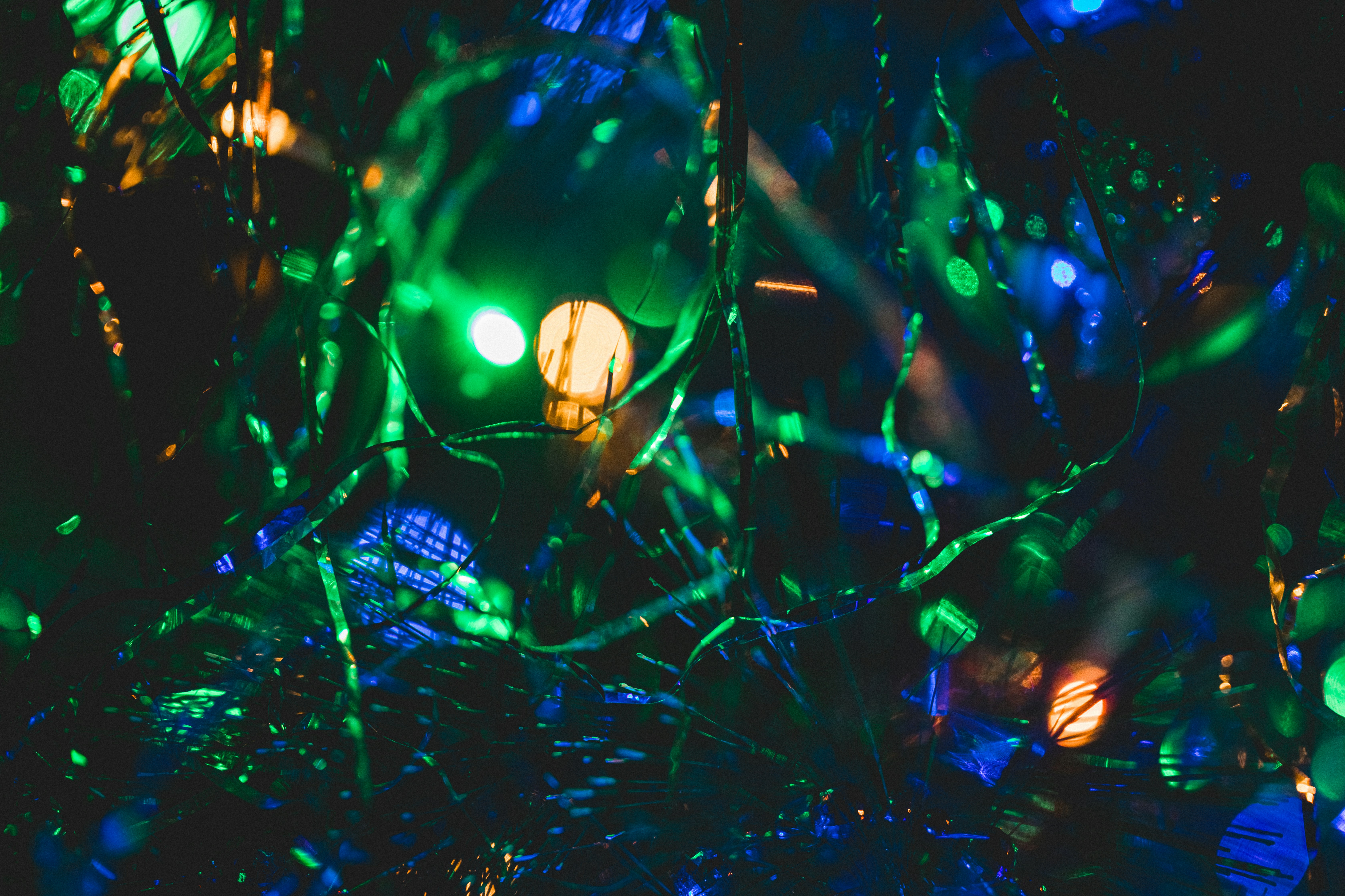 Vibrant strands of green and blue lights intertwine, creating an abstract composition that evokes a festive atmosphere.