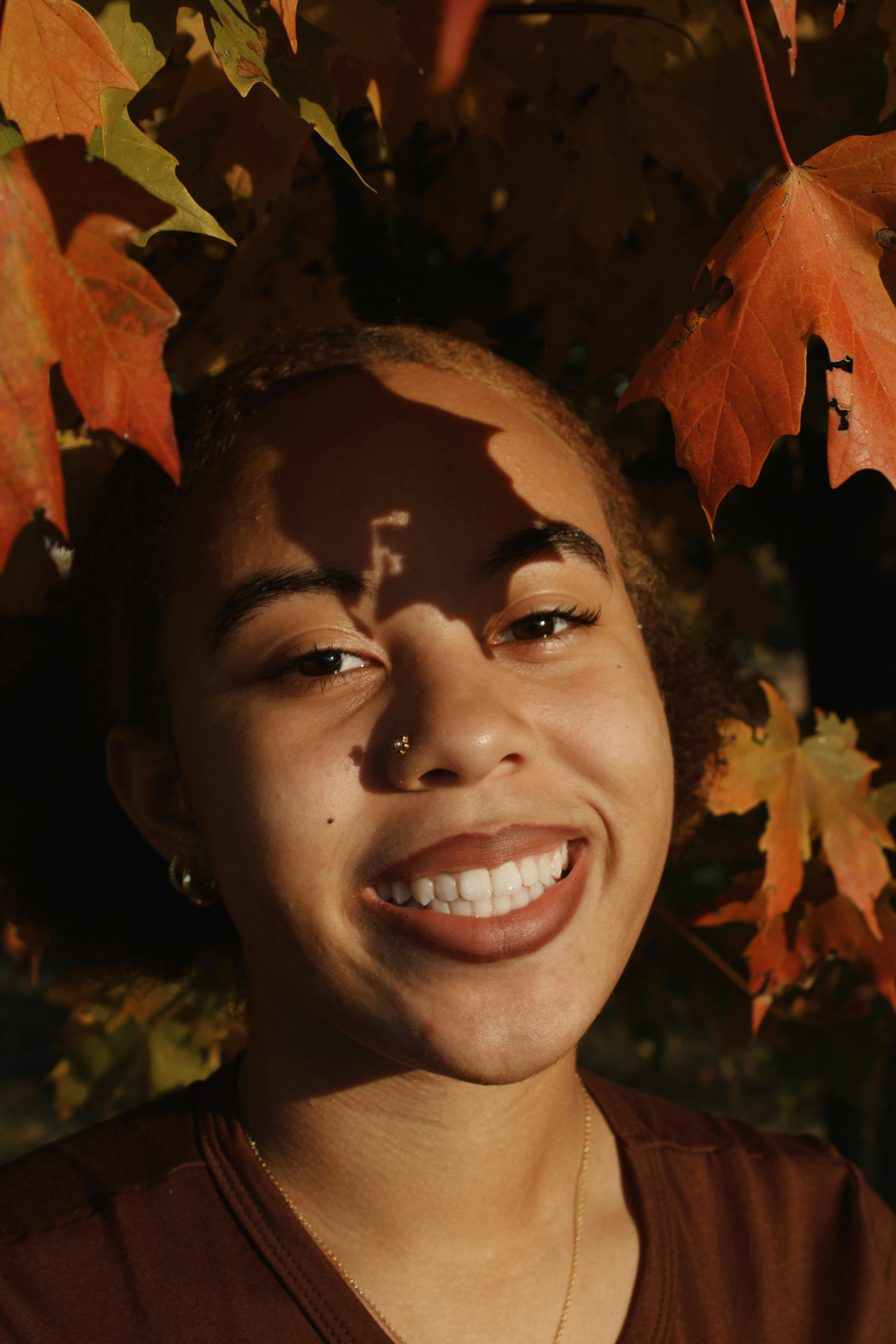 Sunlit Portrait: A Warm Smile Framed by Autumn Leaves