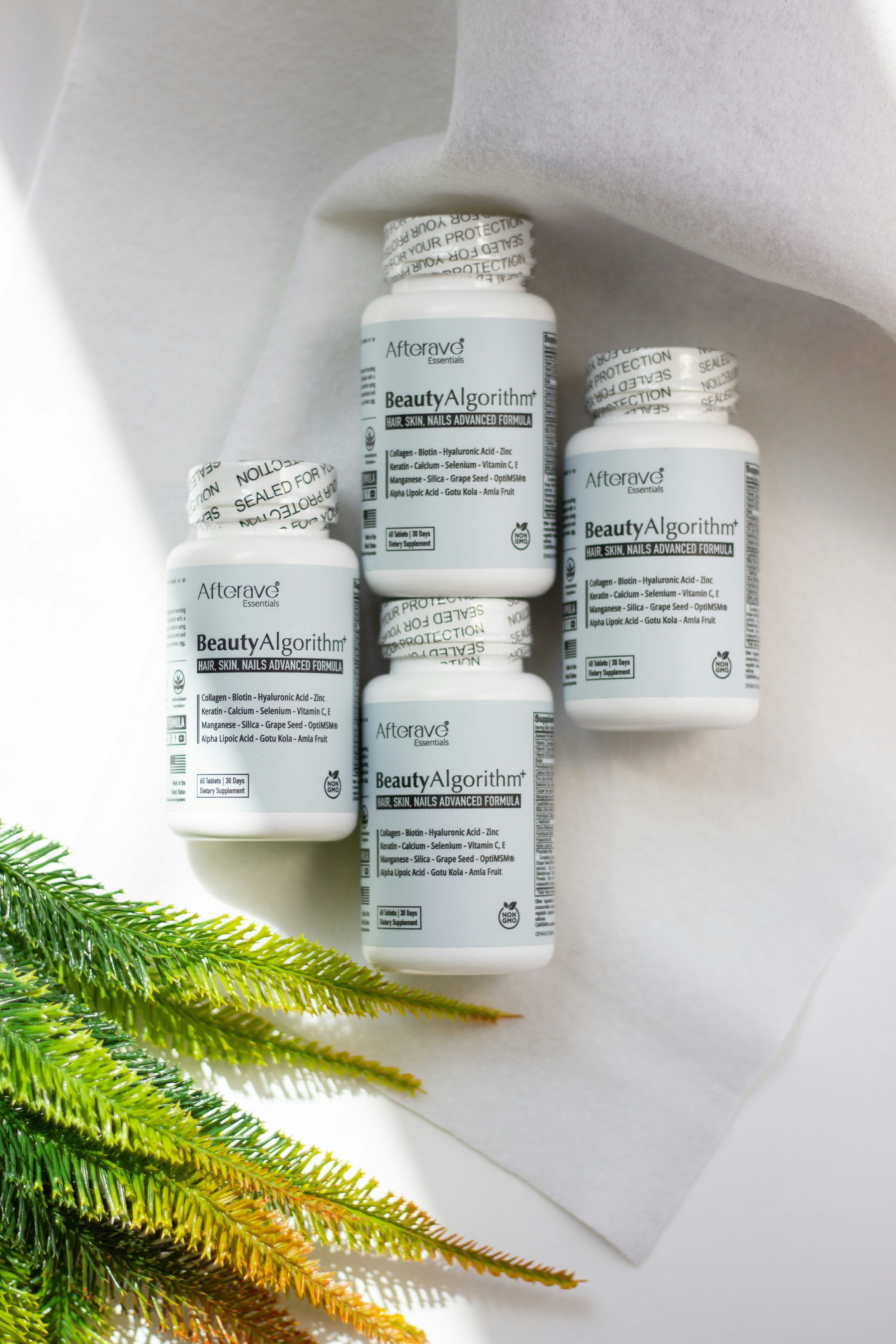 Four bottles of vitamin supplements sitting next to a plant photo ...