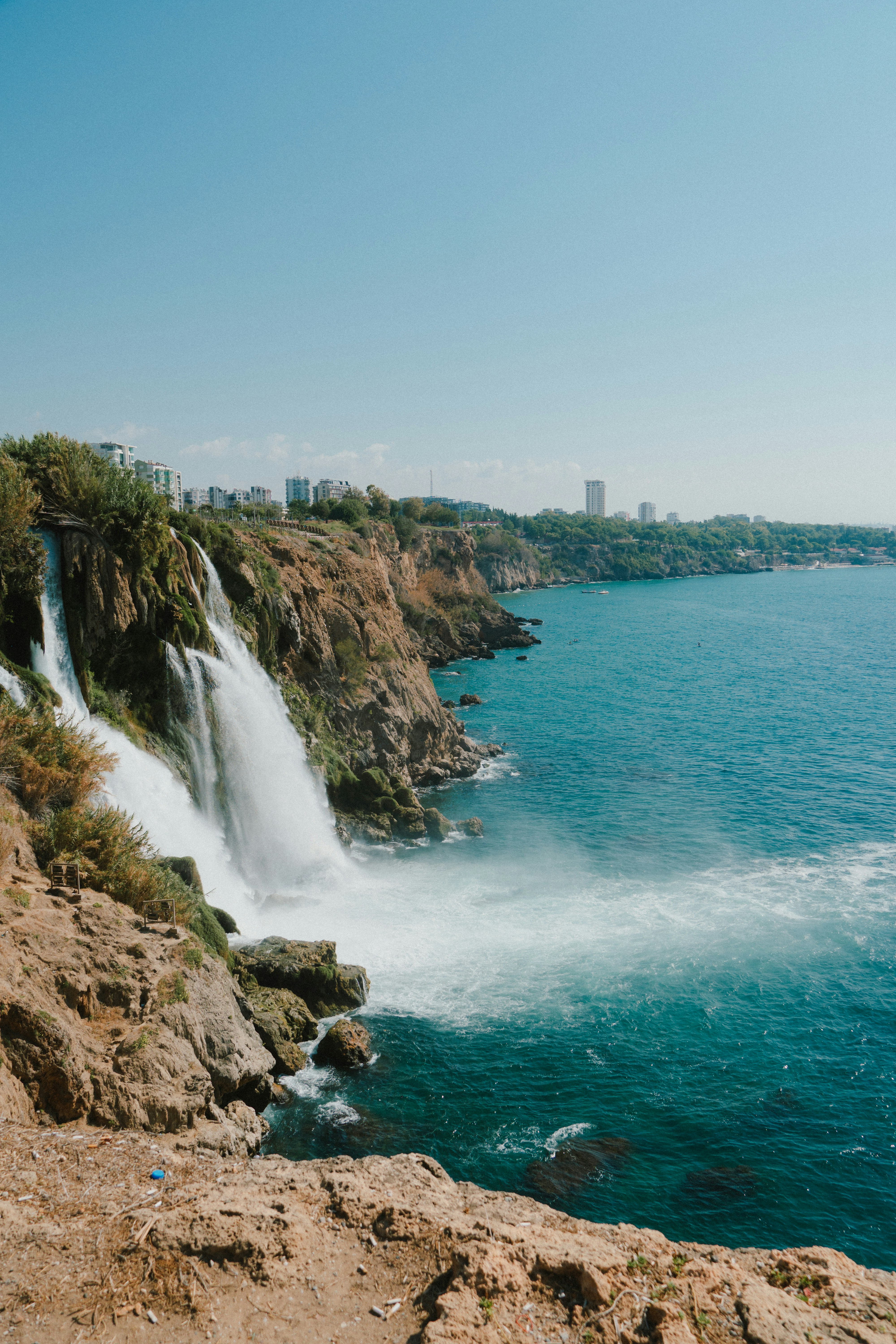 A man standing on the edge of a cliff looking at a waterfall photo ...