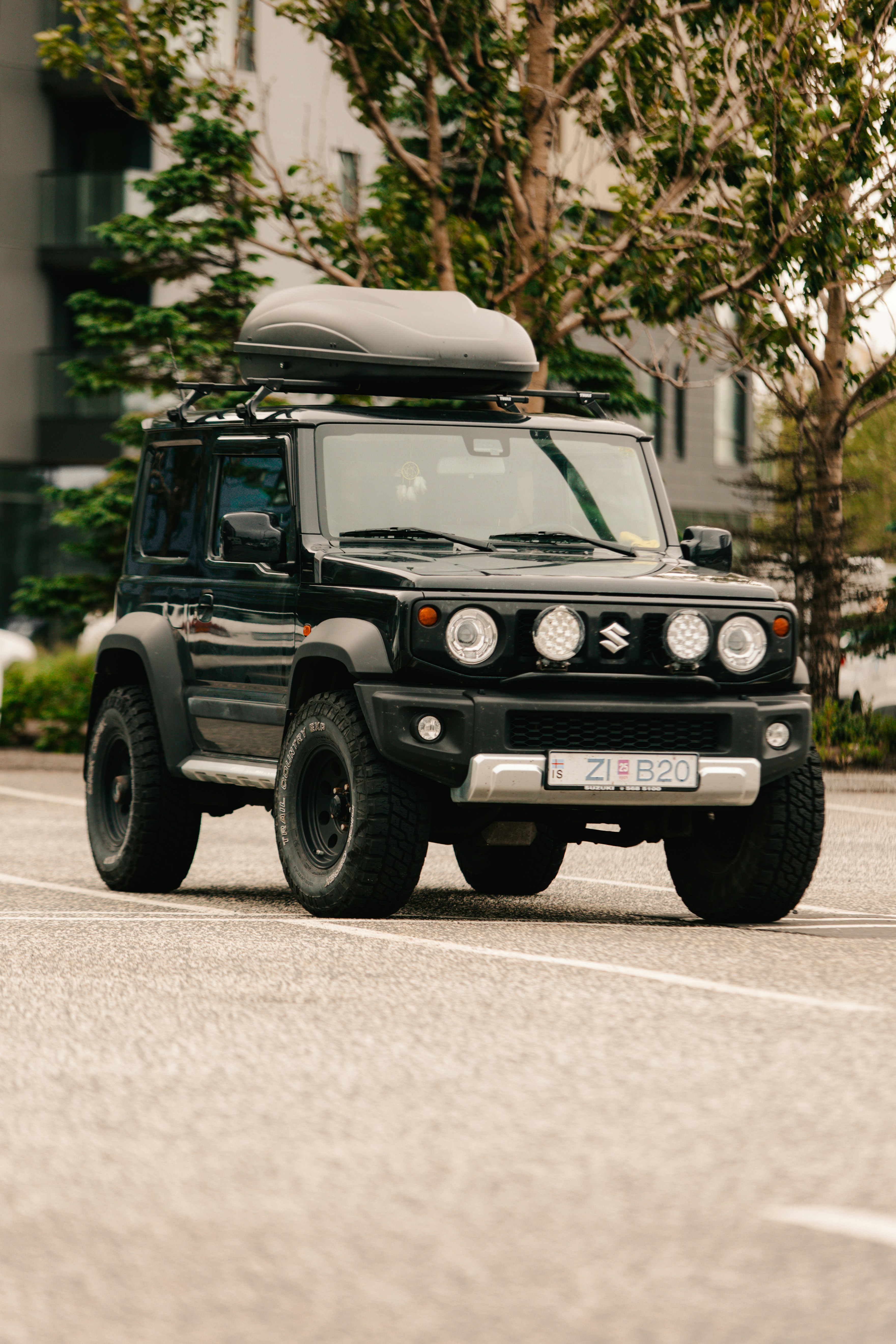 Rugged City Scout: Black Suzuki Jimny with Rooftop Cargo Box Under Urban Light