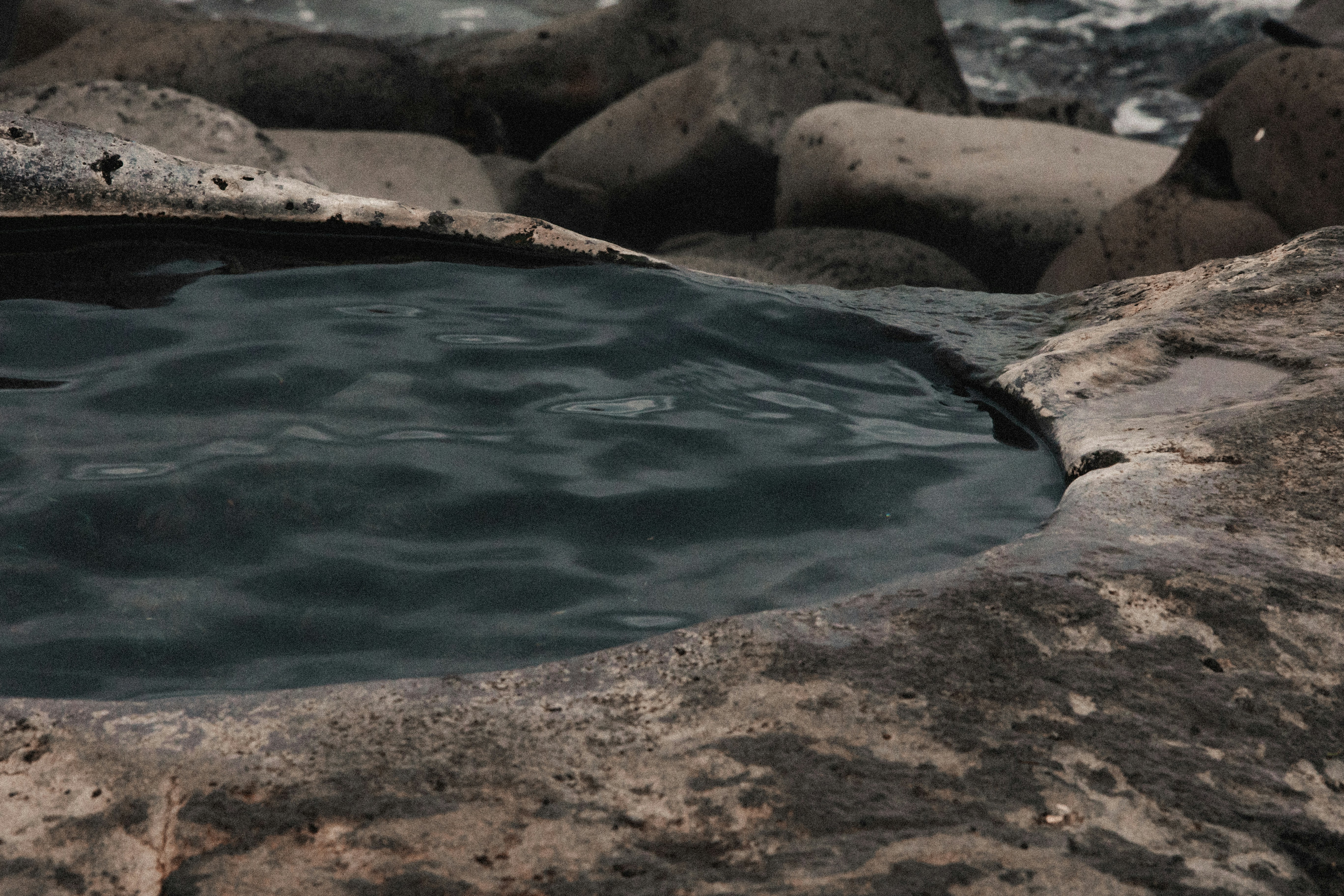 Circular tidal pool nestled in weathered granite along a rugged shoreline
