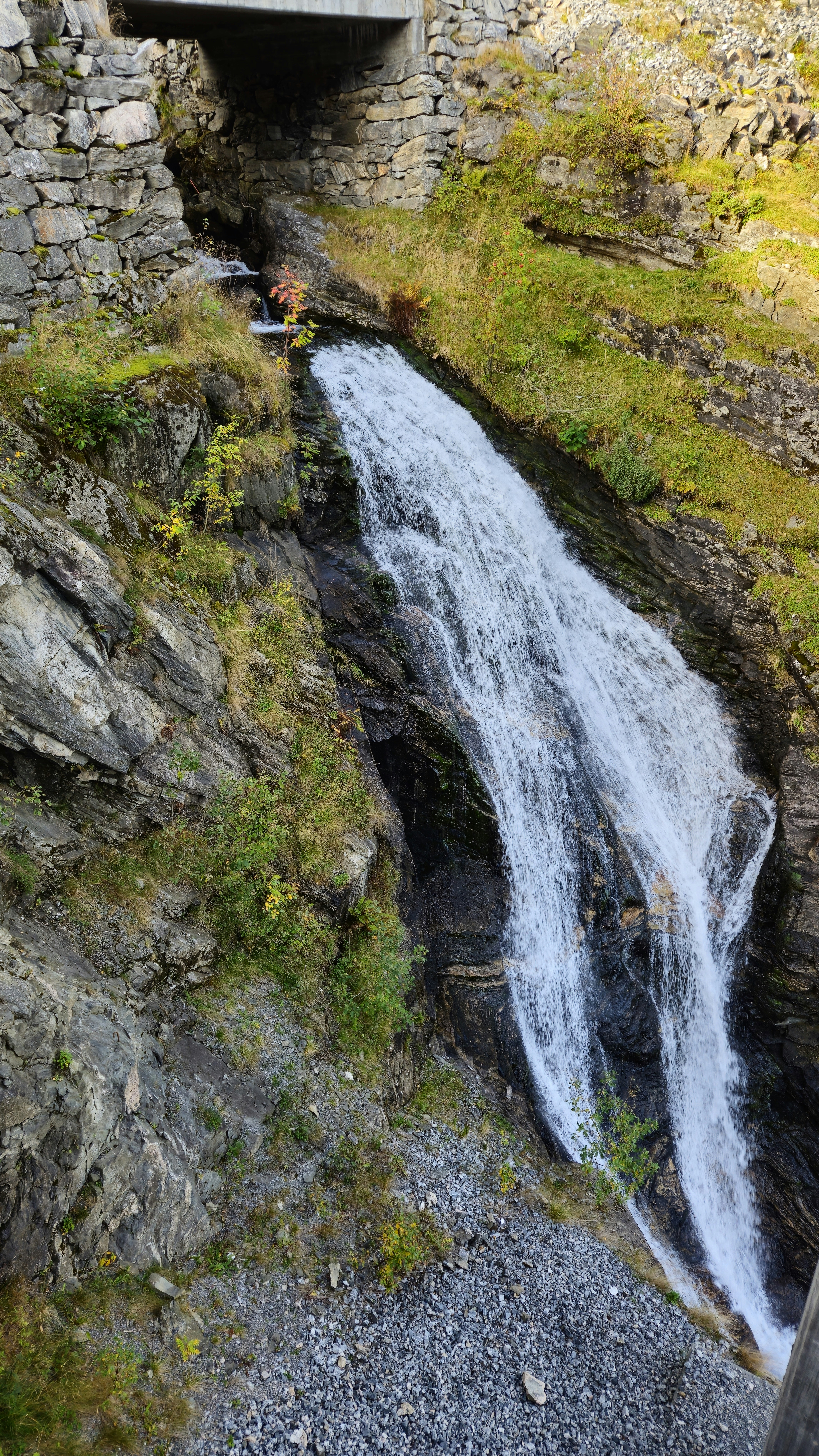 A small waterfall flowing into a river next to a bridge photo – Free ...