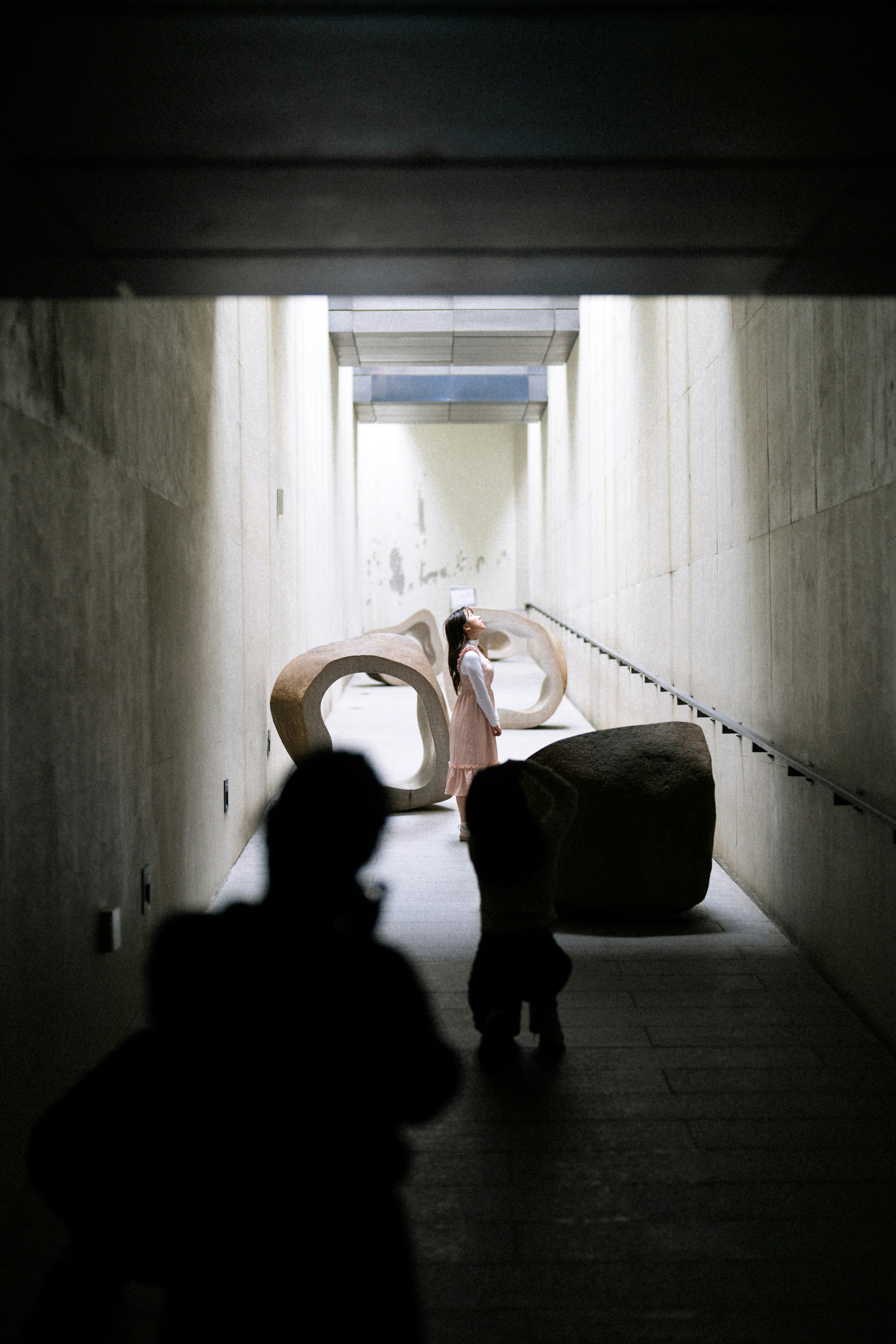 Echoes in Concrete: A Pink-Clad Figure Among Abstract Stone Sculptures