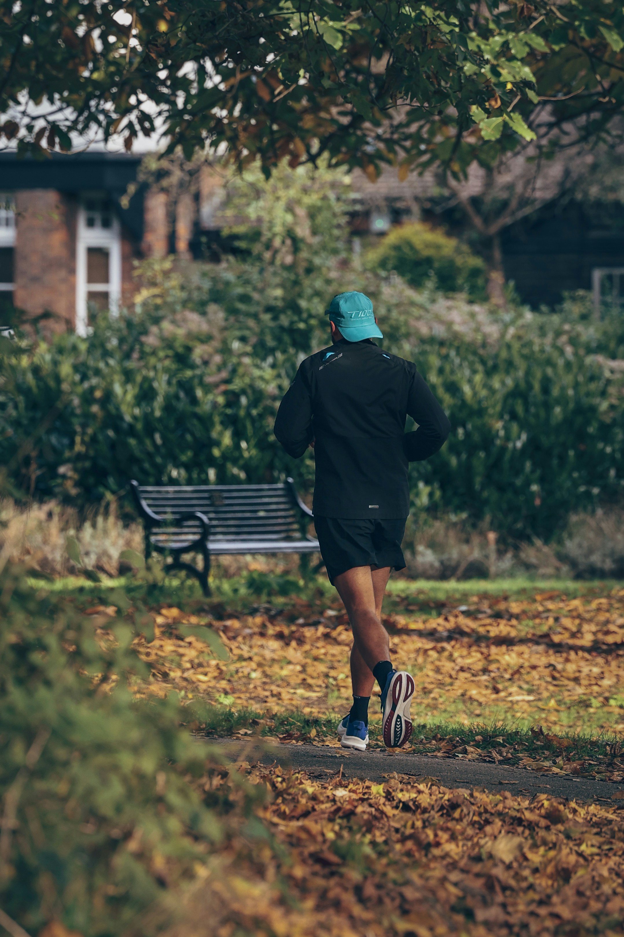A man running in a park with a bench in the background photo – Free ...