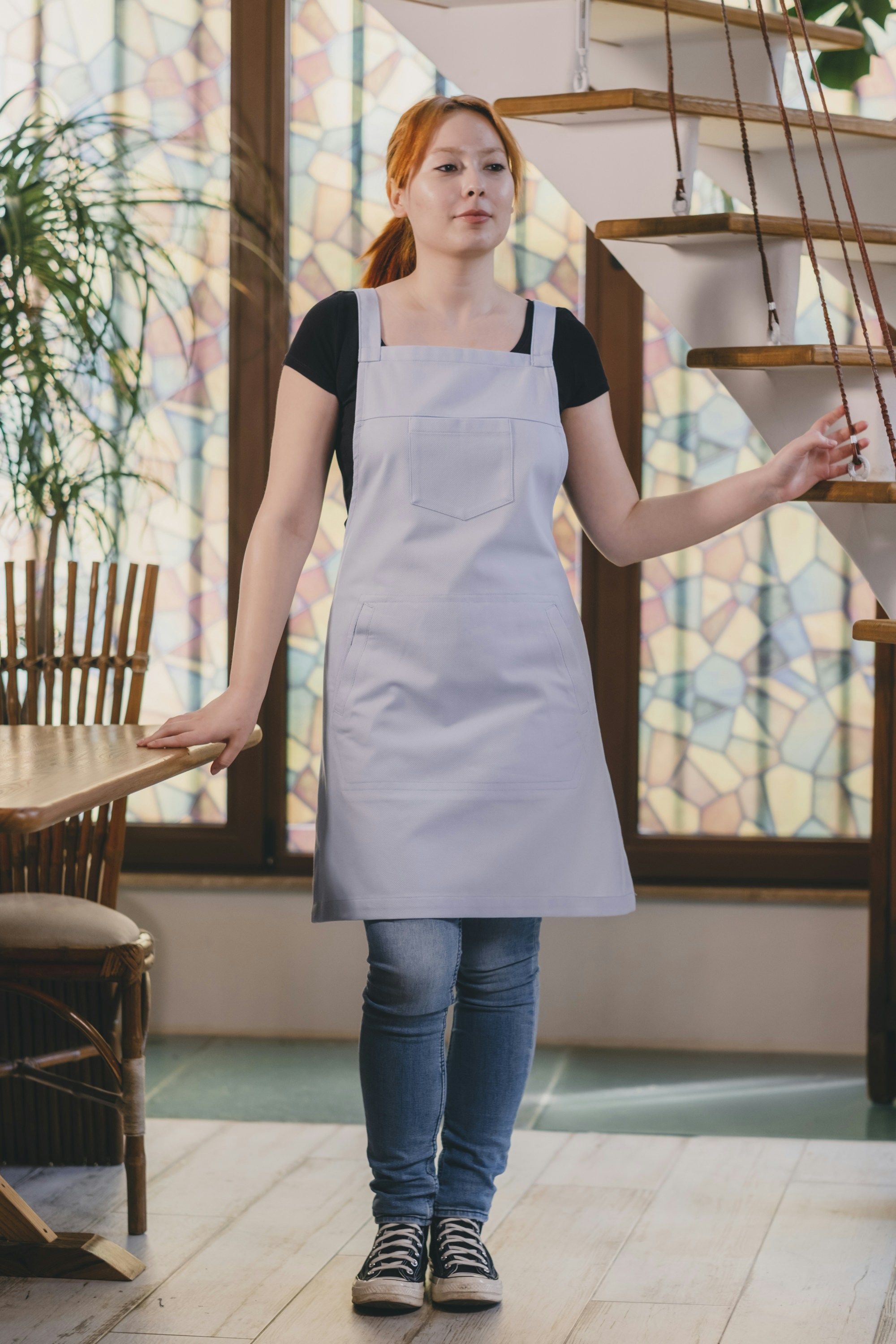 A woman in an apron standing in front of a stair case photo – Free ...
