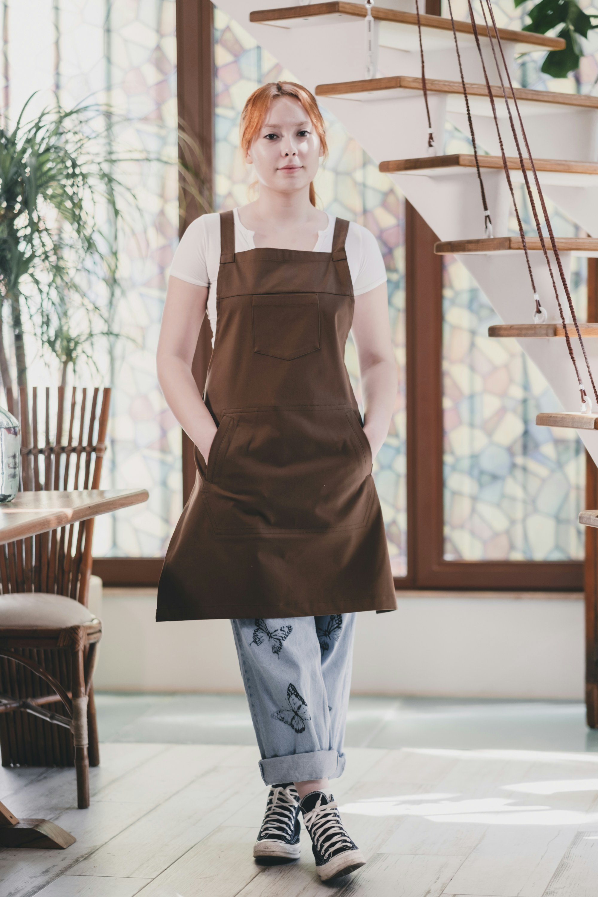 A woman in a brown apron standing in front of a staircase photo – Free ...