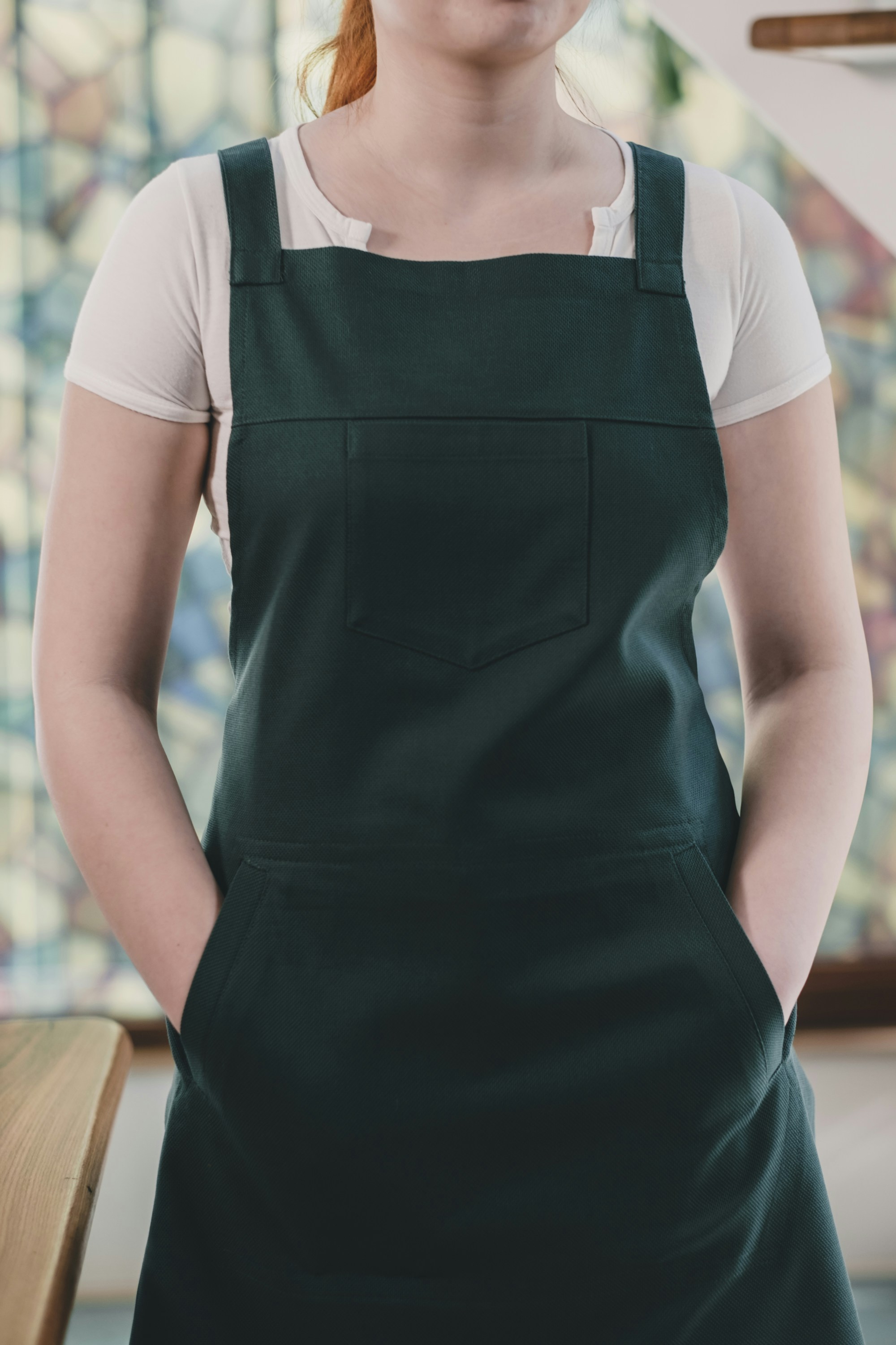 A woman wearing a green apron standing in front of a stained glass ...