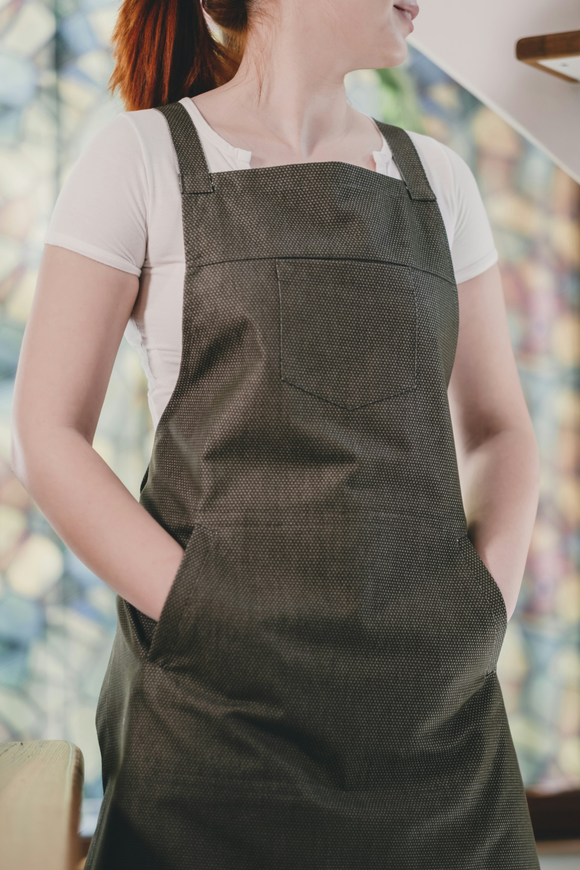 A woman wearing an apron standing in front of a stained glass window ...
