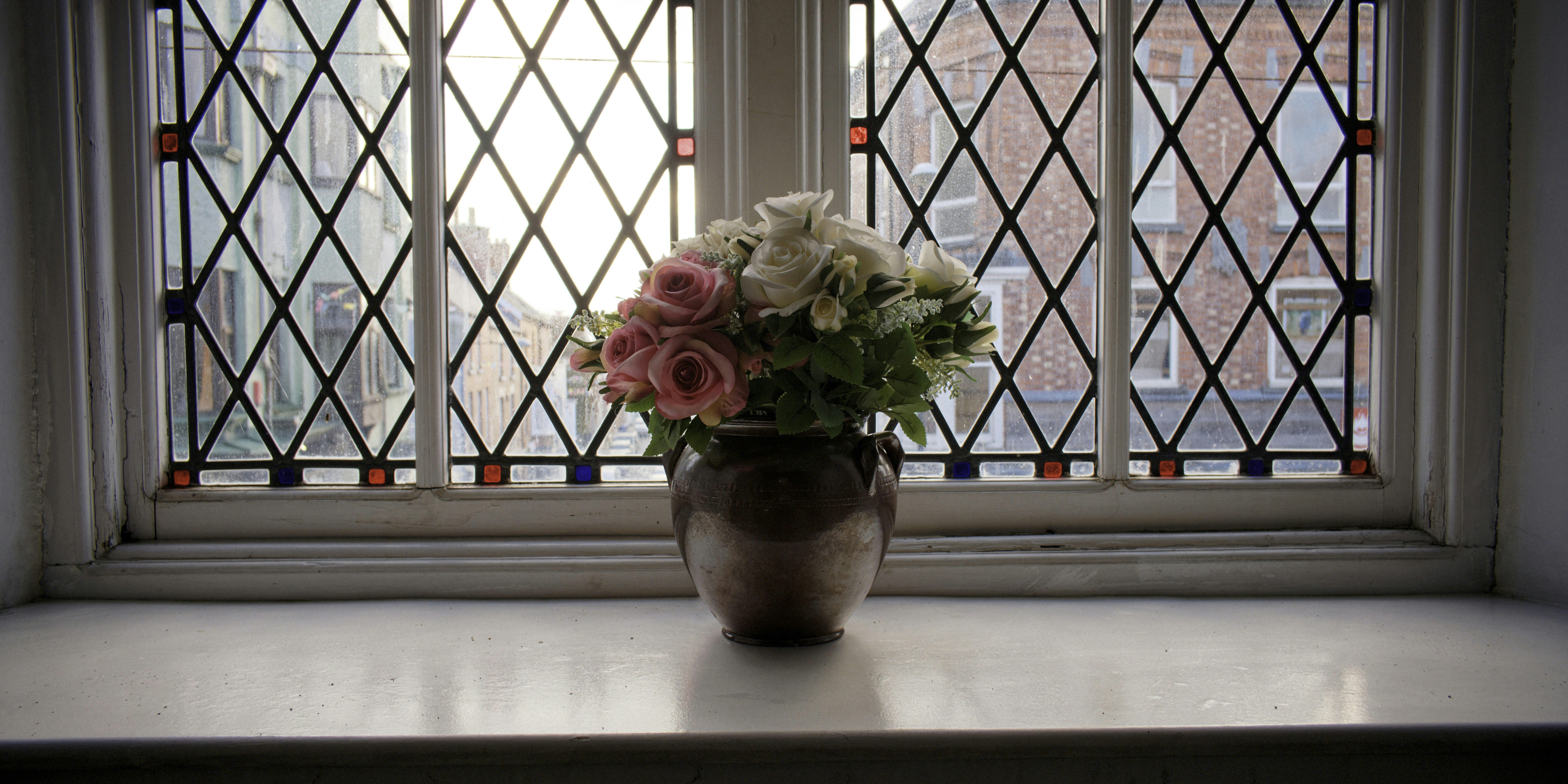 Between Light and Lattice: Vase of Roses on a Windowsill