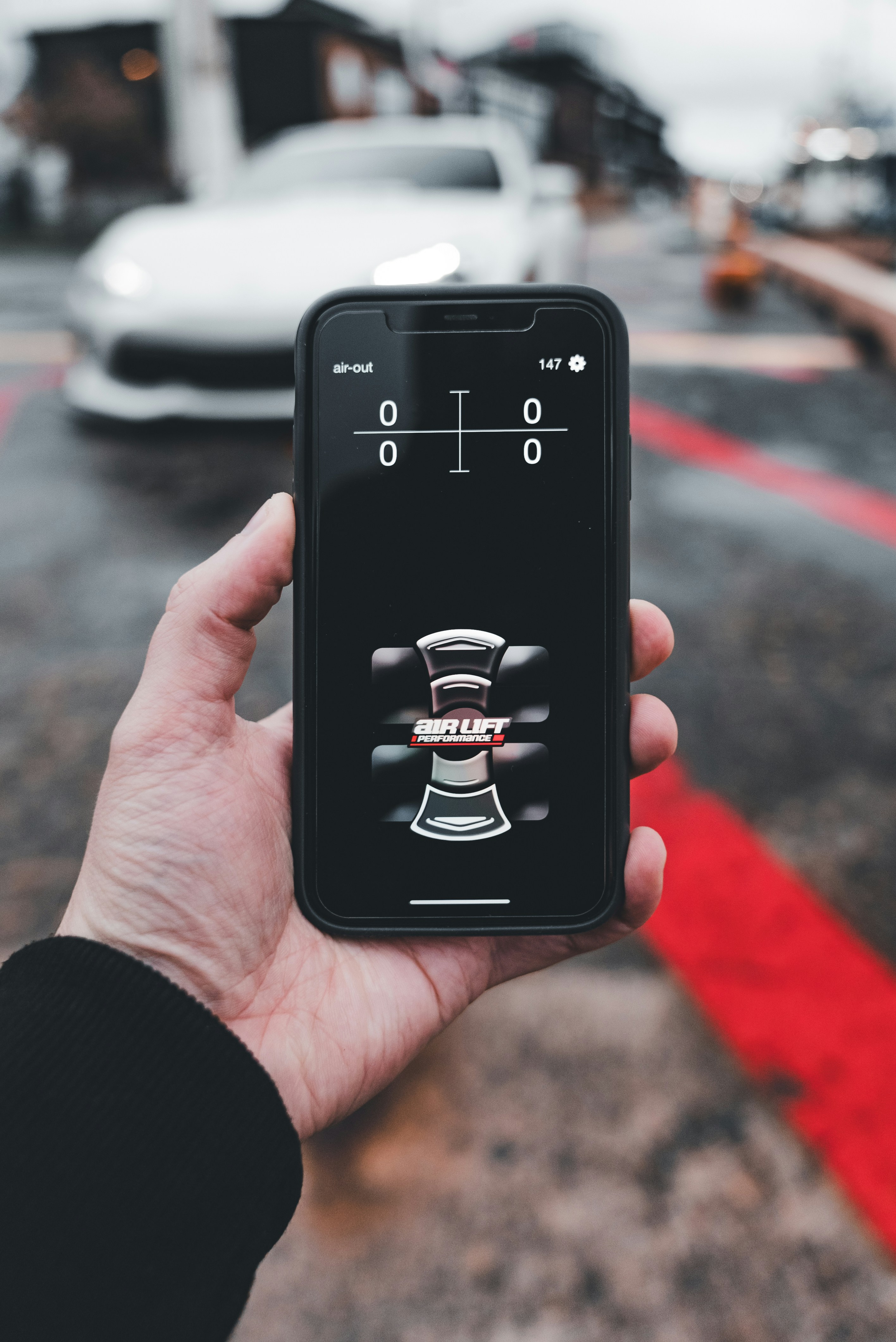 Phone in hand framing a blurred race car scene on a rainy street