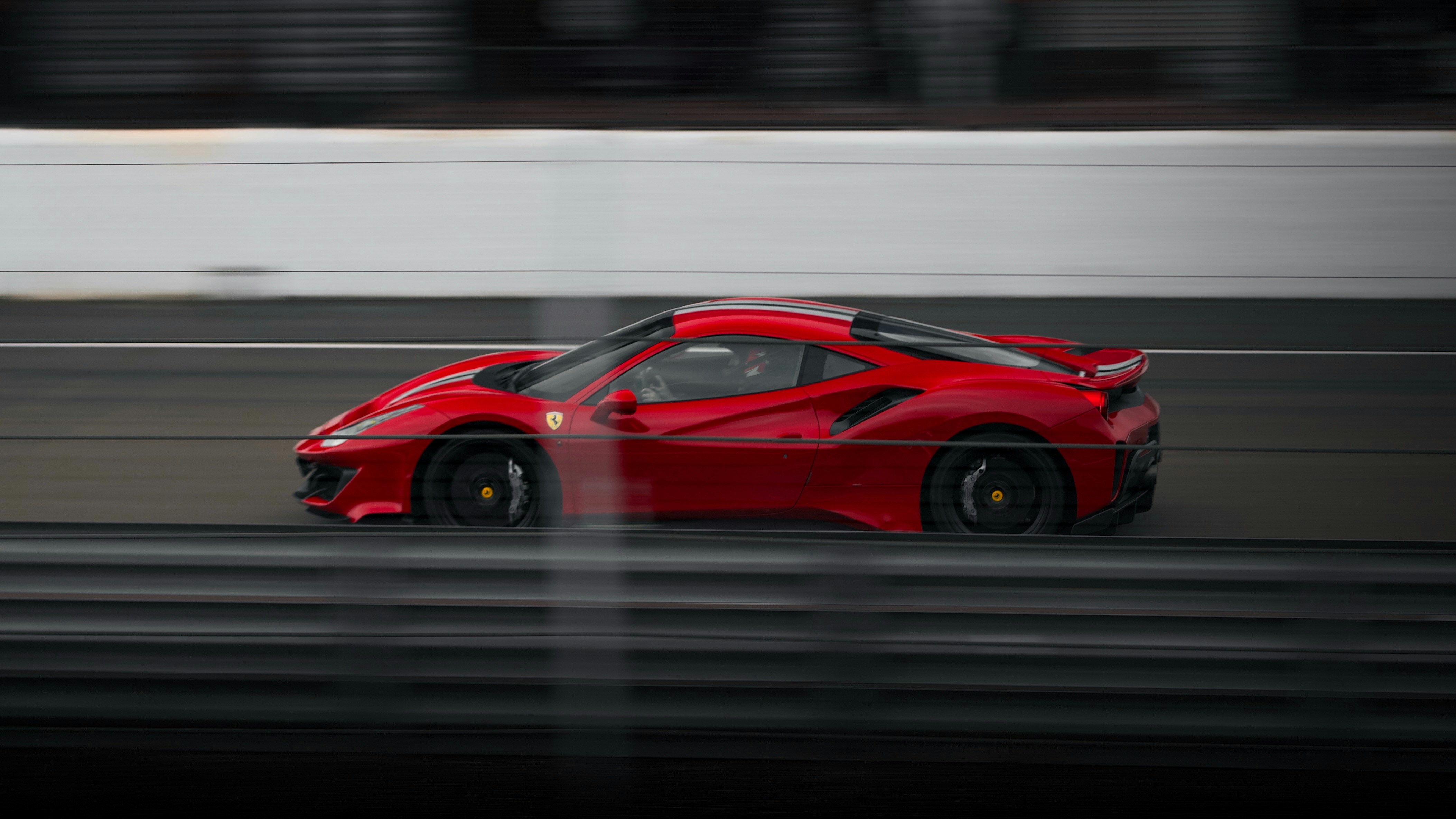 Red Ferrari 488 Pista speeding along a racetrack with motion blur effect.