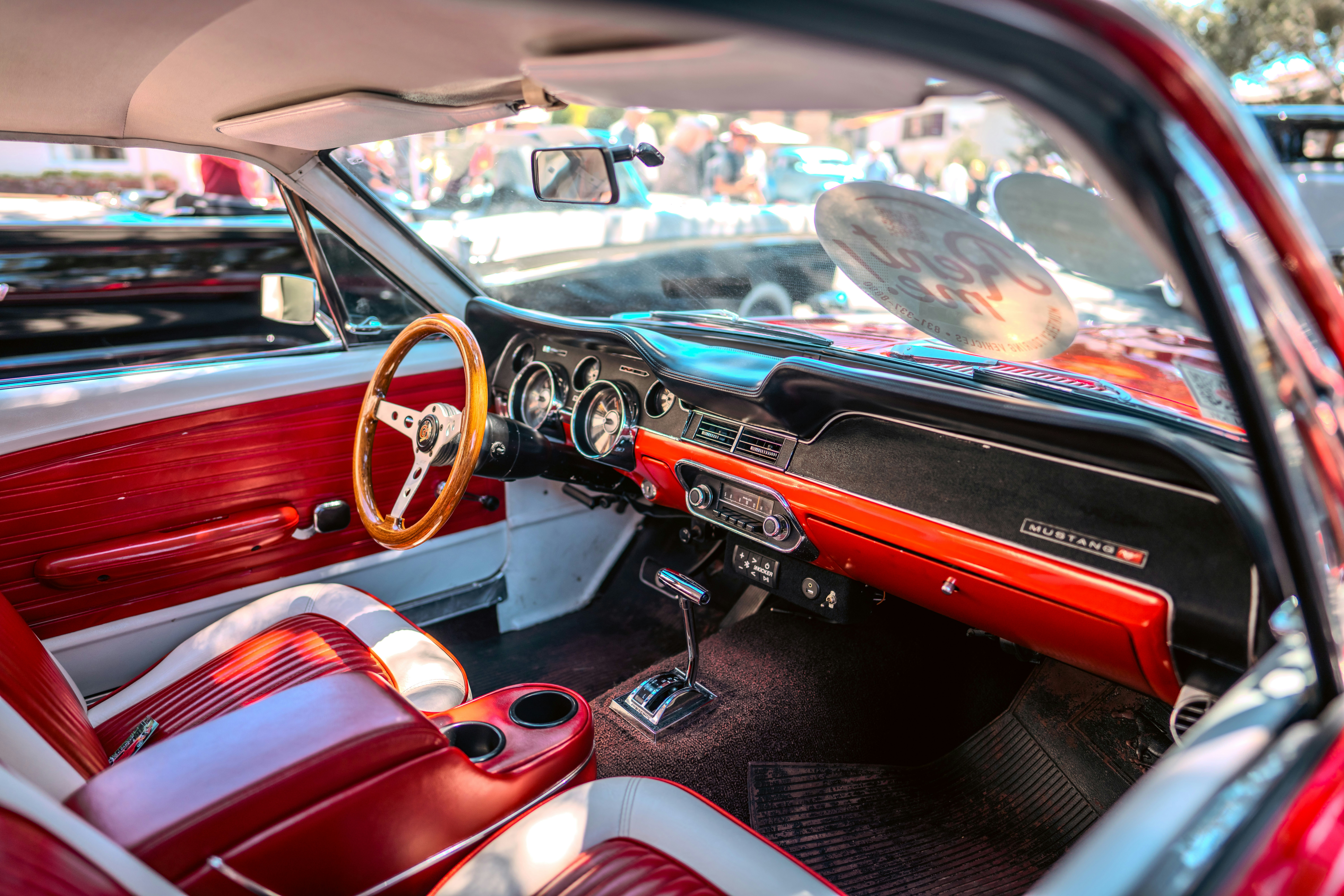 Crimson Cockpit: A Classic Car's Red Dash, Wood Wheel, and Chrome Gauges