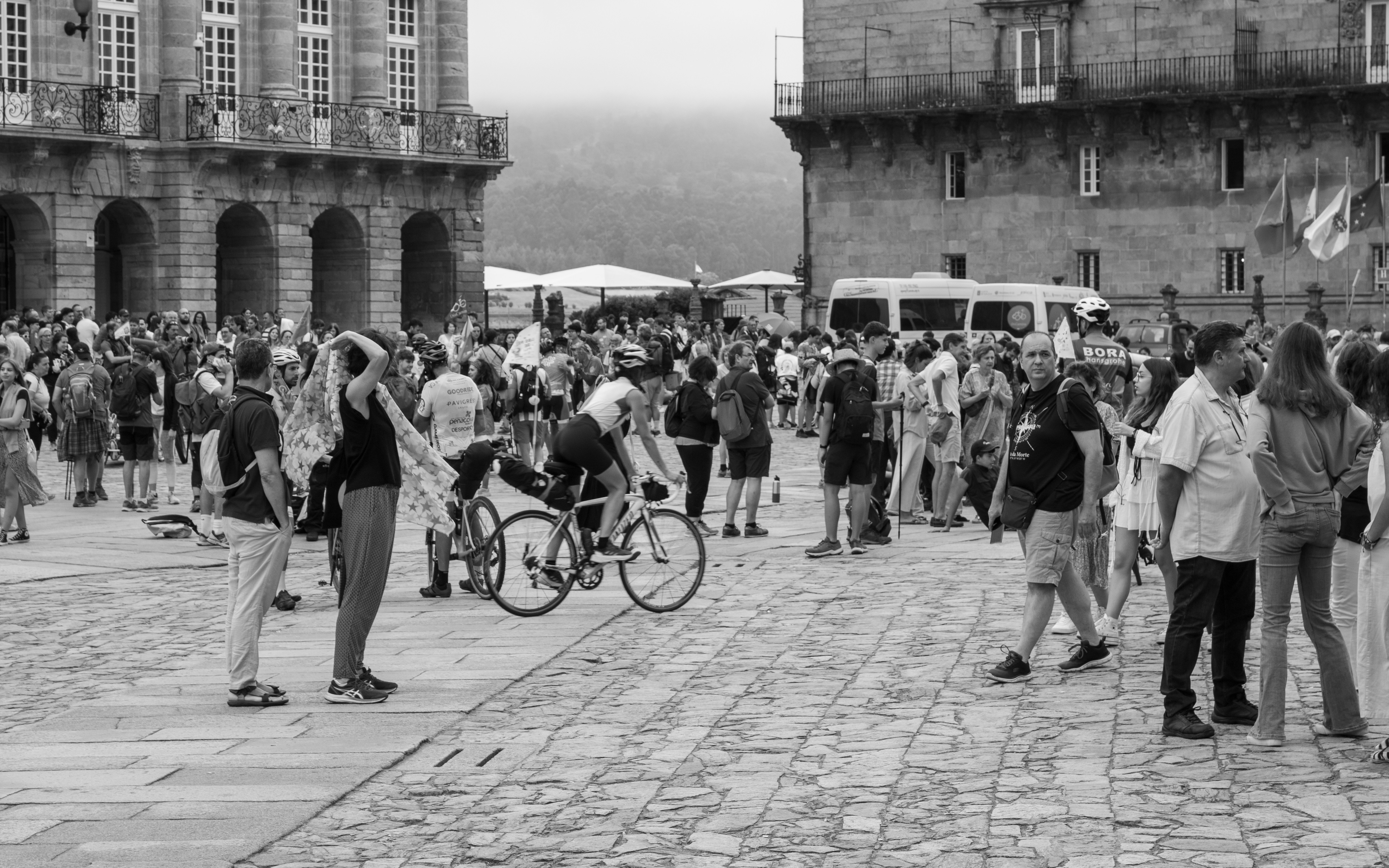 A bustling public square filled with people, cyclists, and vendors, showcasing the vibrancy of urban life in black and white.