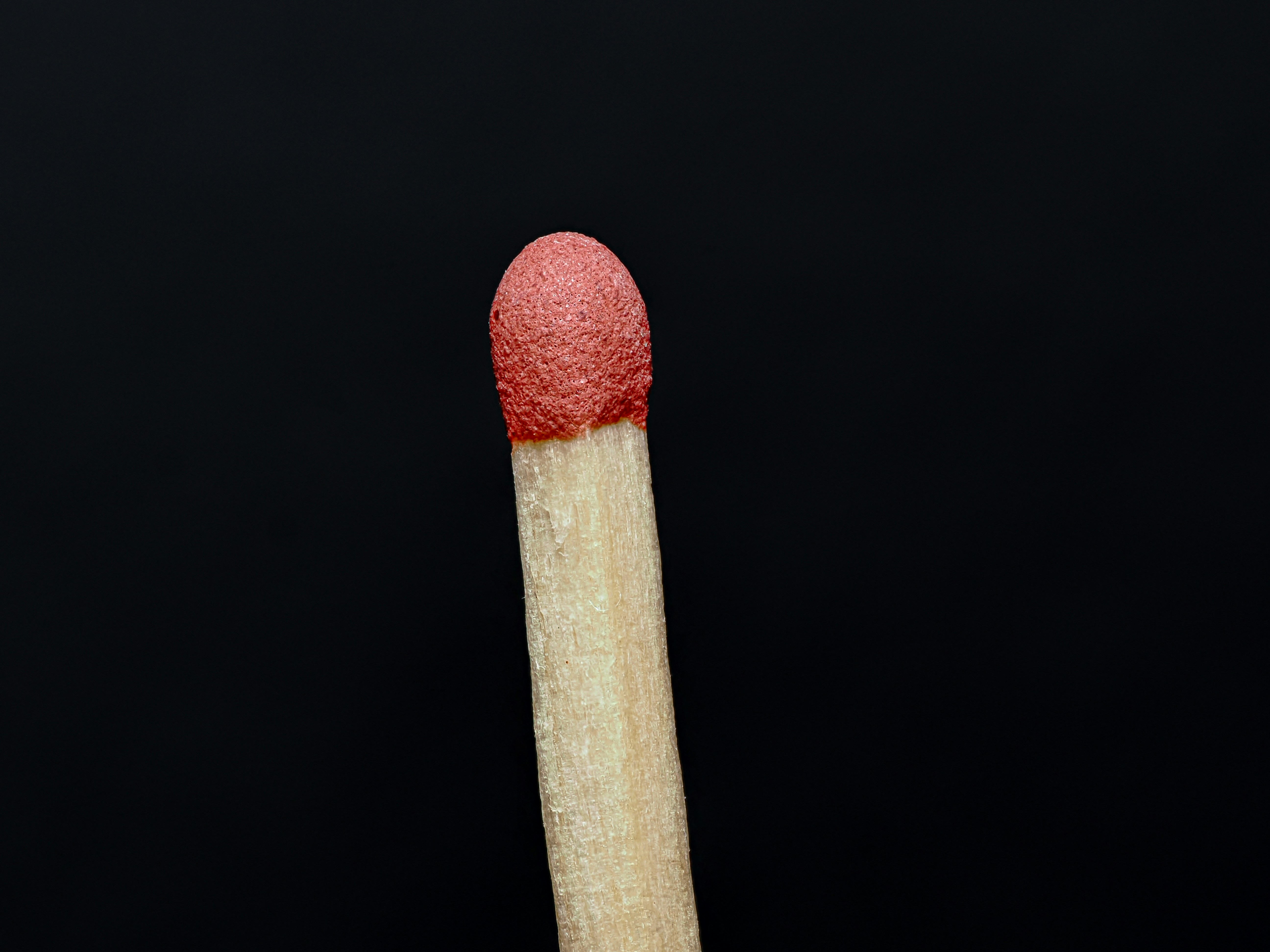 Close-up of matchstick against black background | A matchstick with a red tip sticking out of it