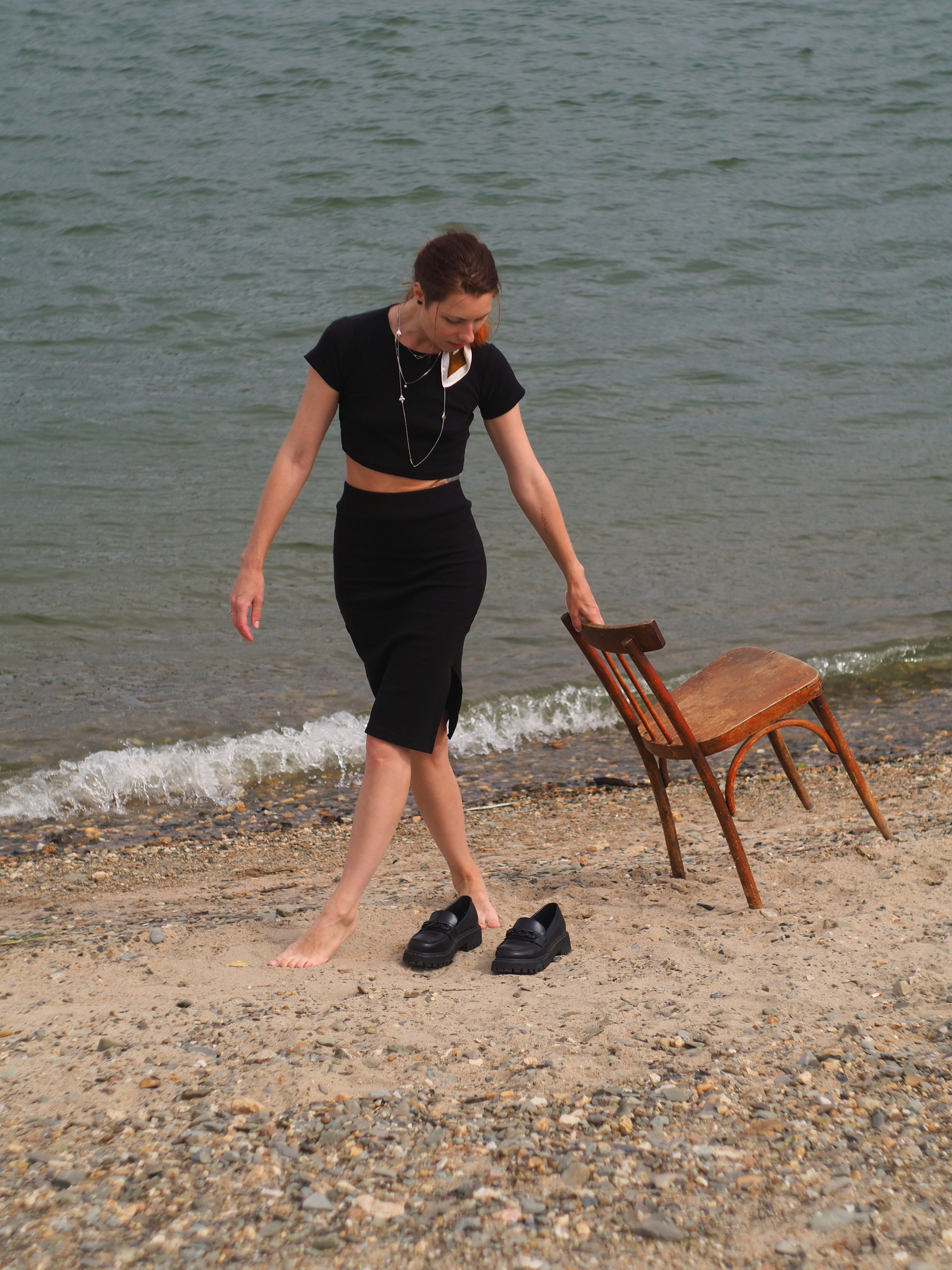 Barefoot stride by the shore: a poised moment beside a lone chair