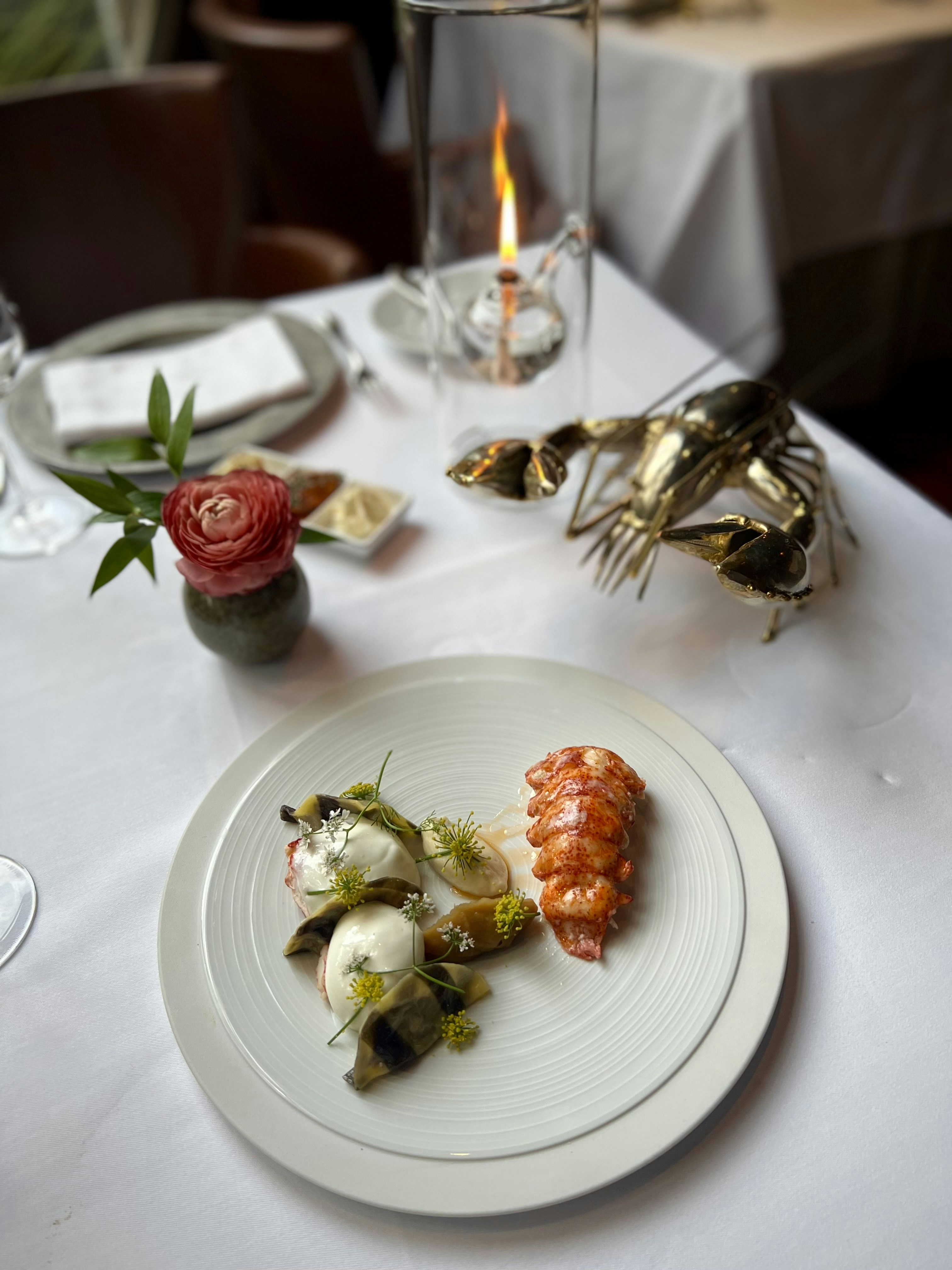 Candlelit Lobster Plate with Floral Accent on White Tablecloth
