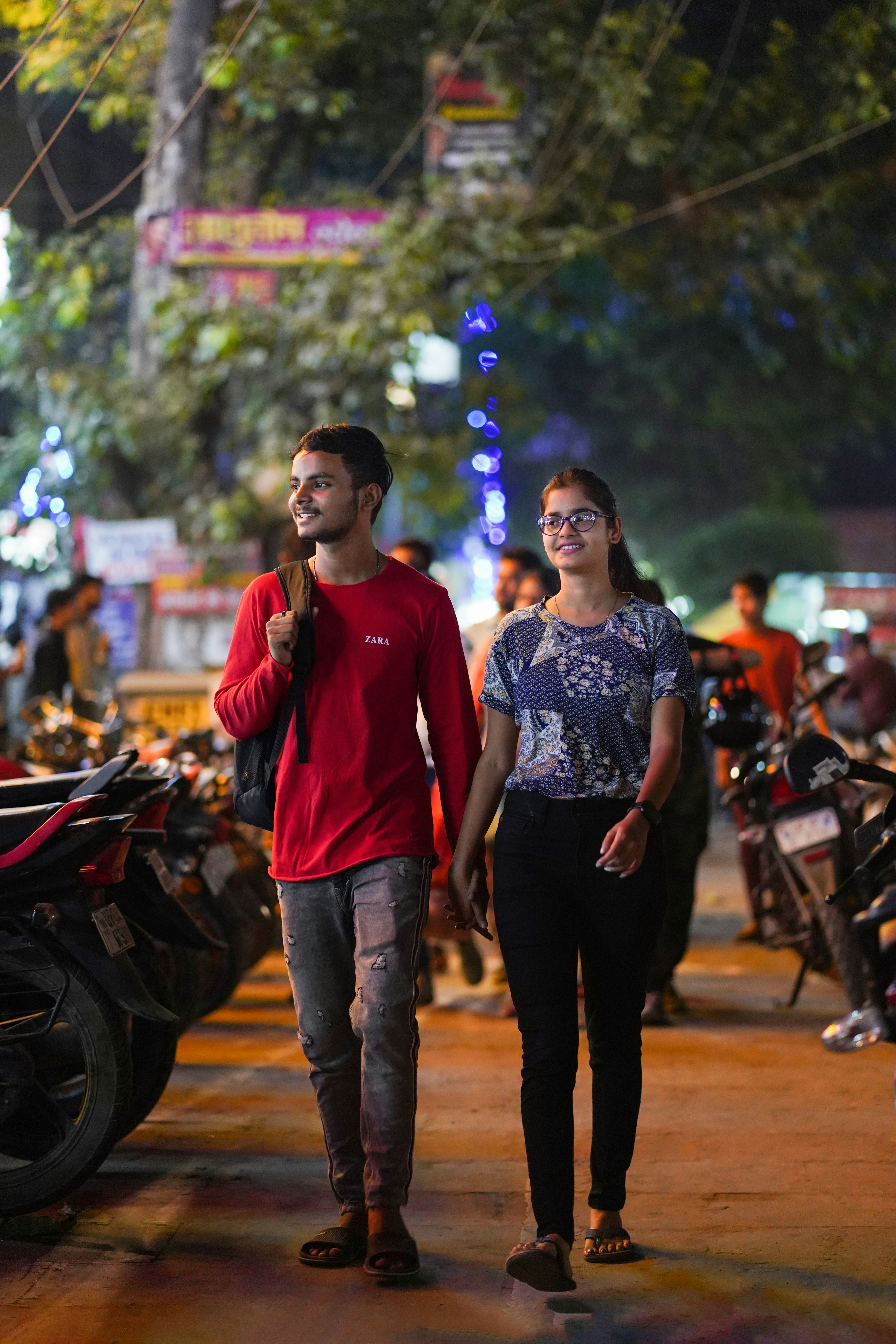 City stroll under neon glow: friends share a moment on a lively street