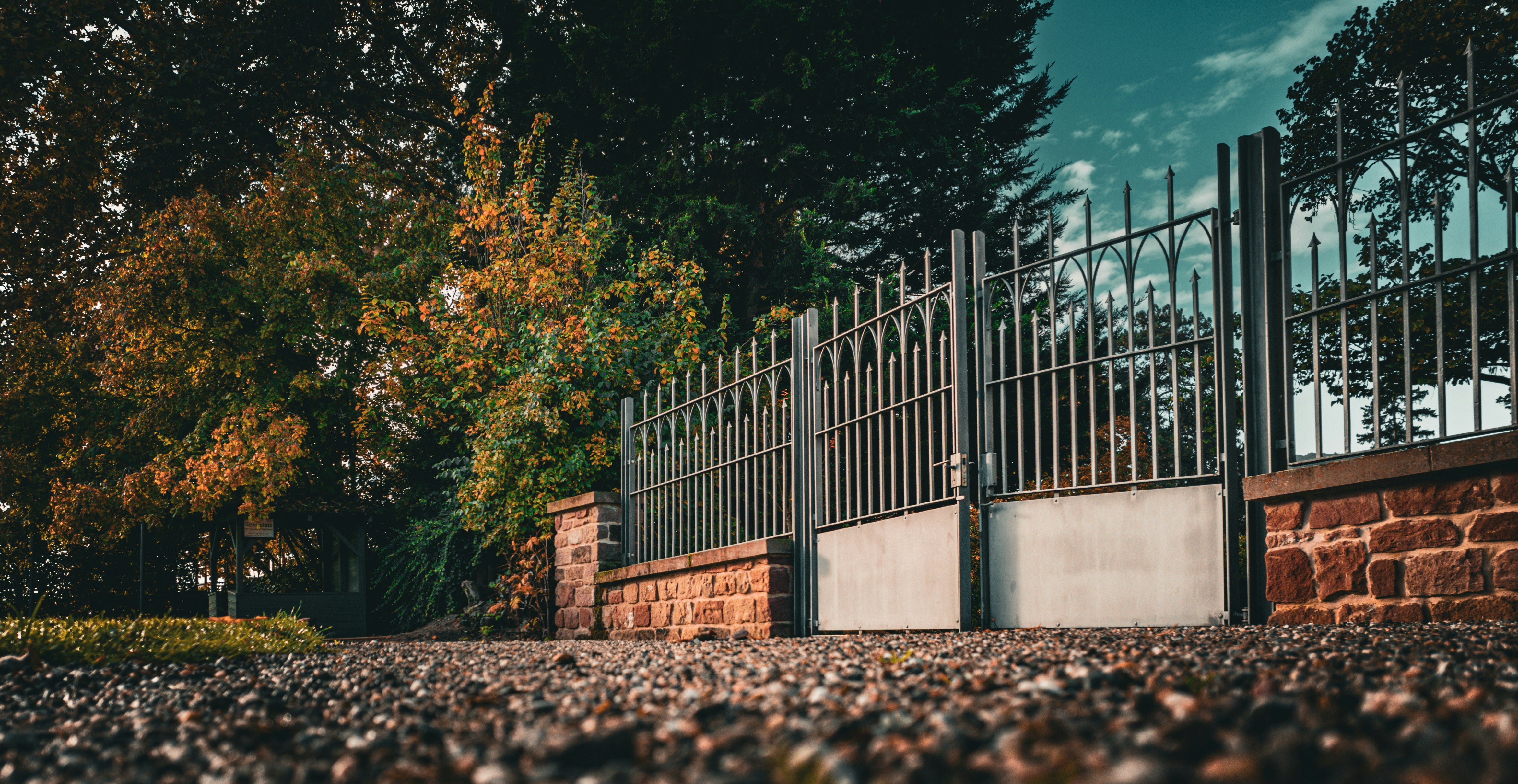 Iron Gate at the Gravel Edge: Autumn Light Framing a Quiet Fence