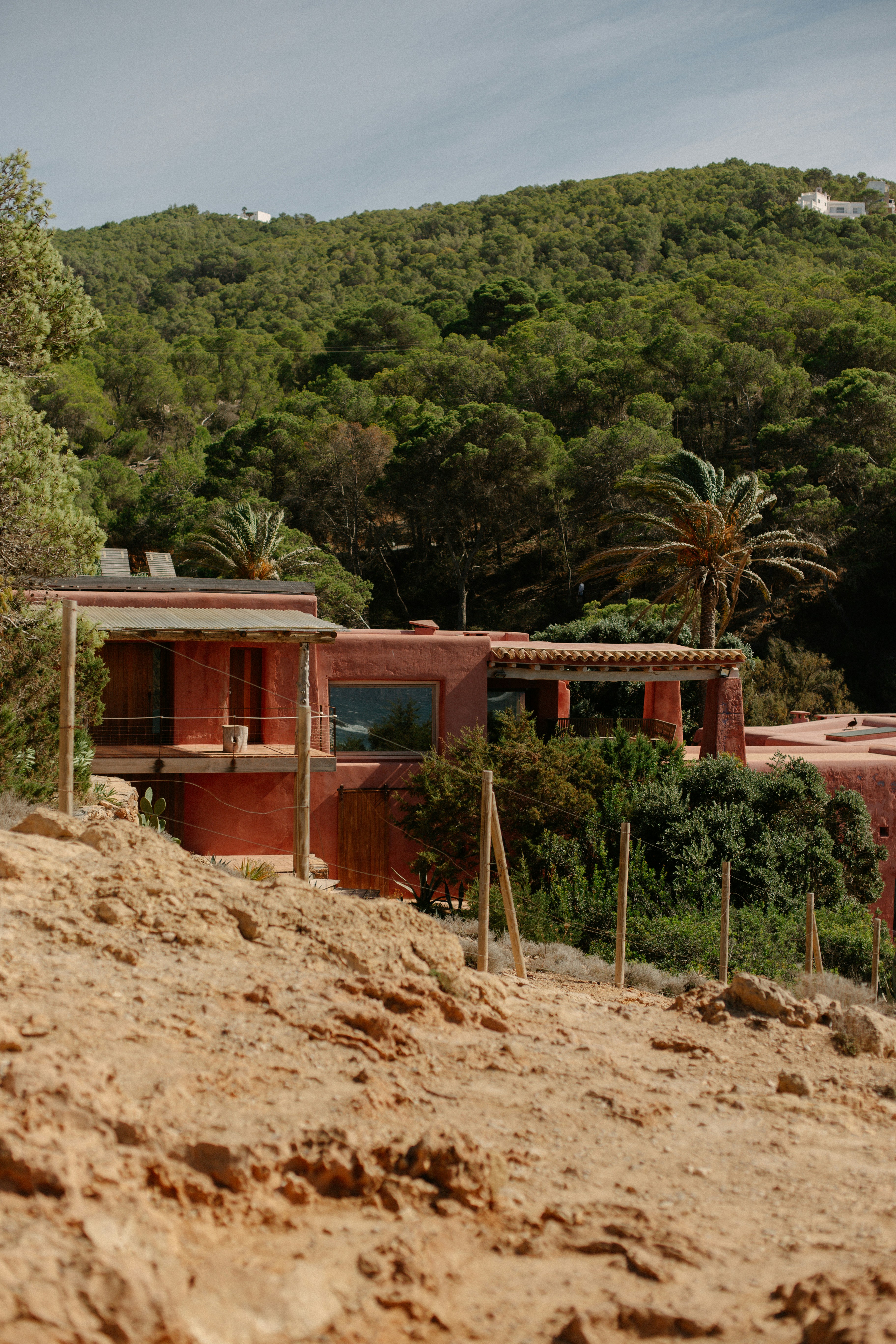 Terracotta Ridge: A Red Villa Anchored on a Dusty Slope Beneath Pine Canopy