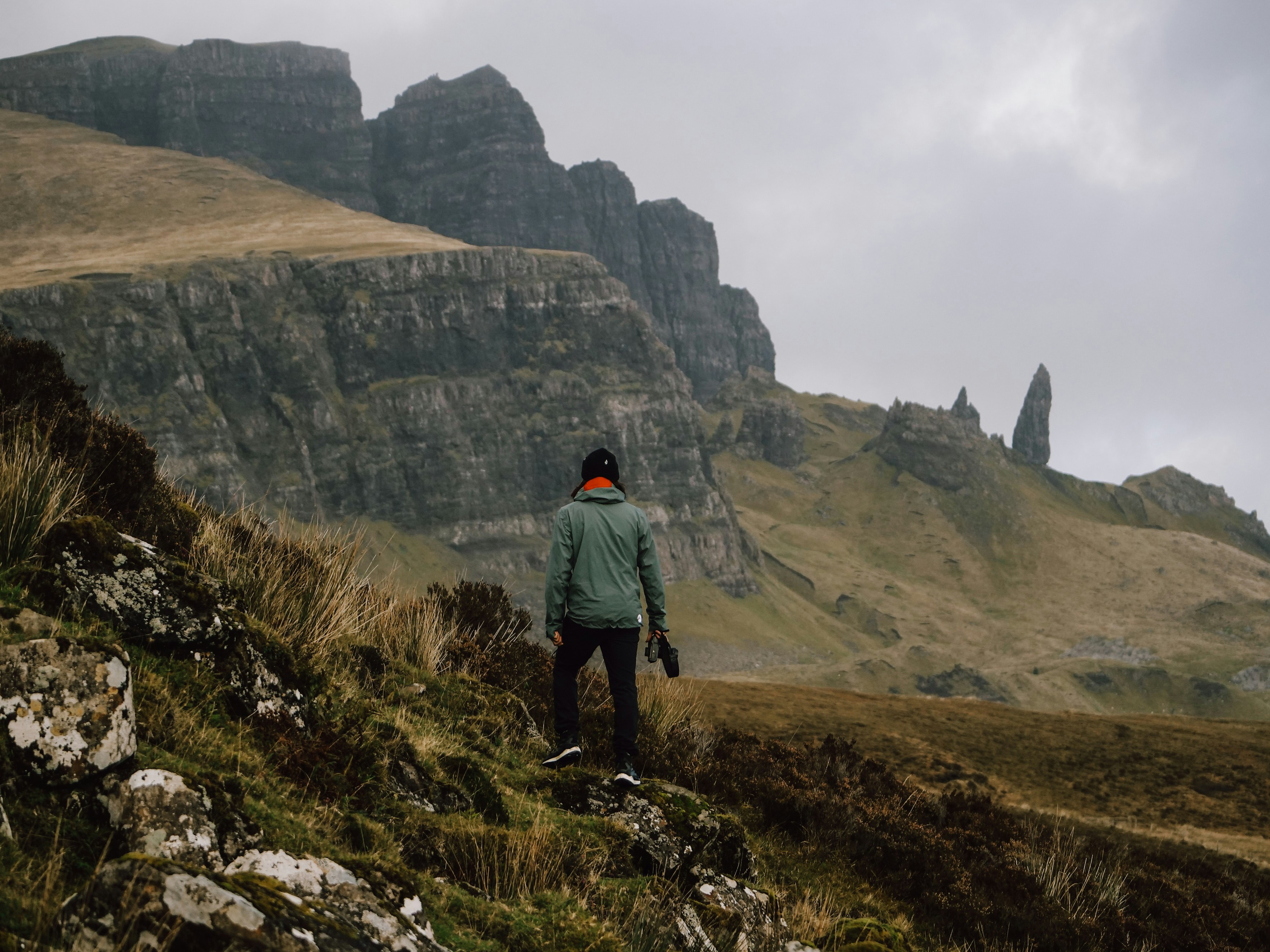 A man walking up a hill on a cloudy day