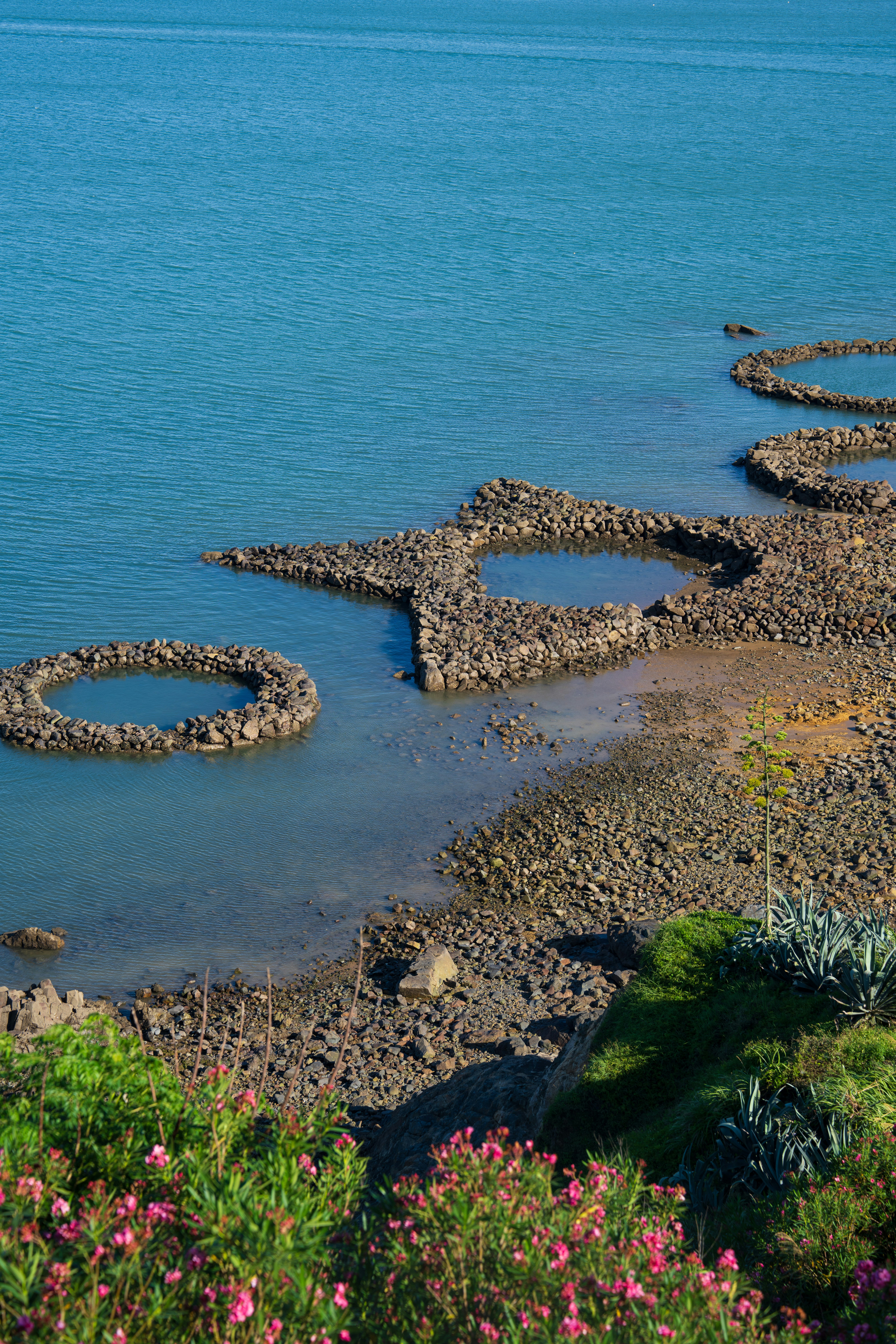 Rings of Rock and Tide: Circular Breakwaters Under a Blue Expanse