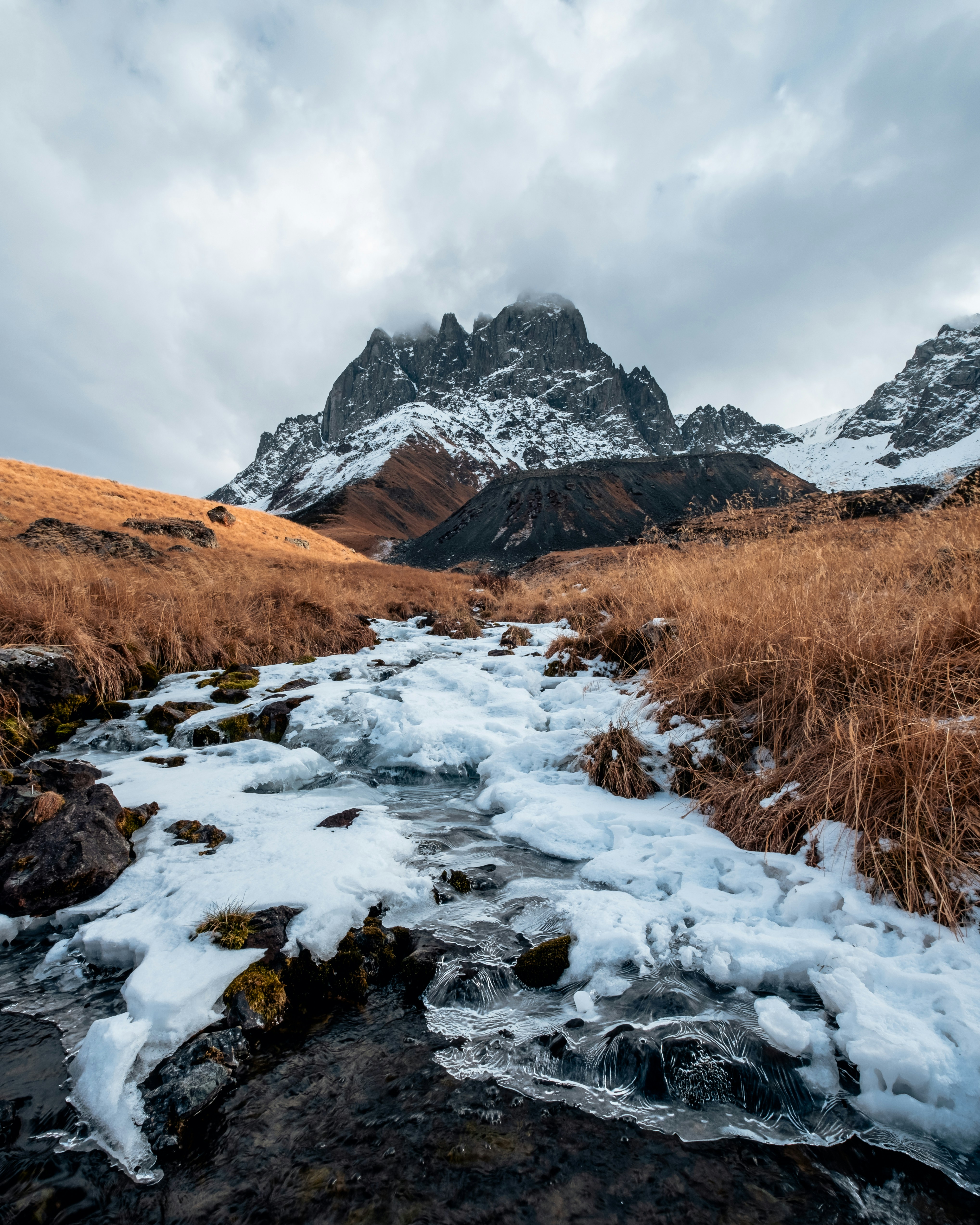 Snow-Capped Summit Framed by Golden Tundra and a Frozen Creek