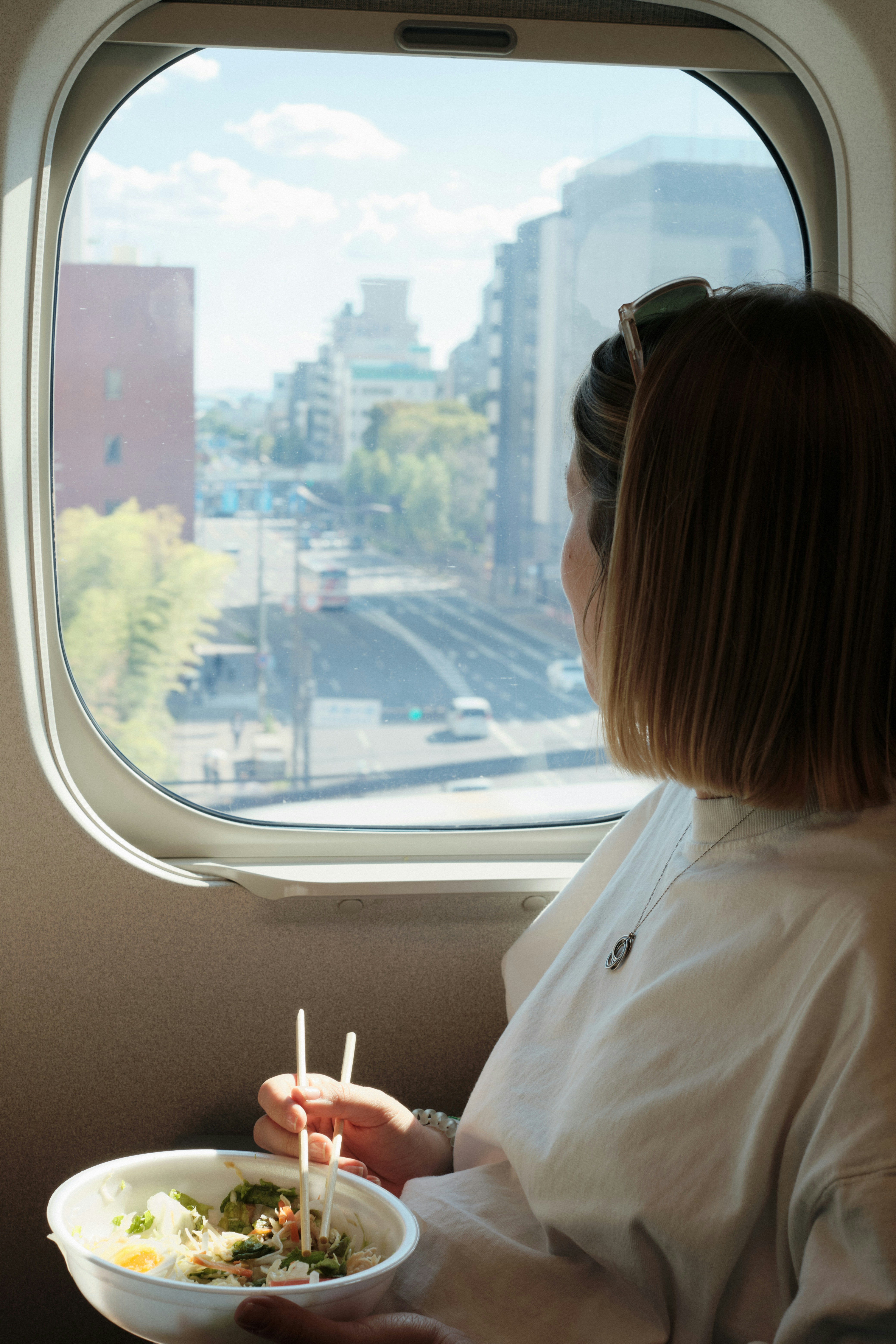 A woman holding a bowl of food in front of a window