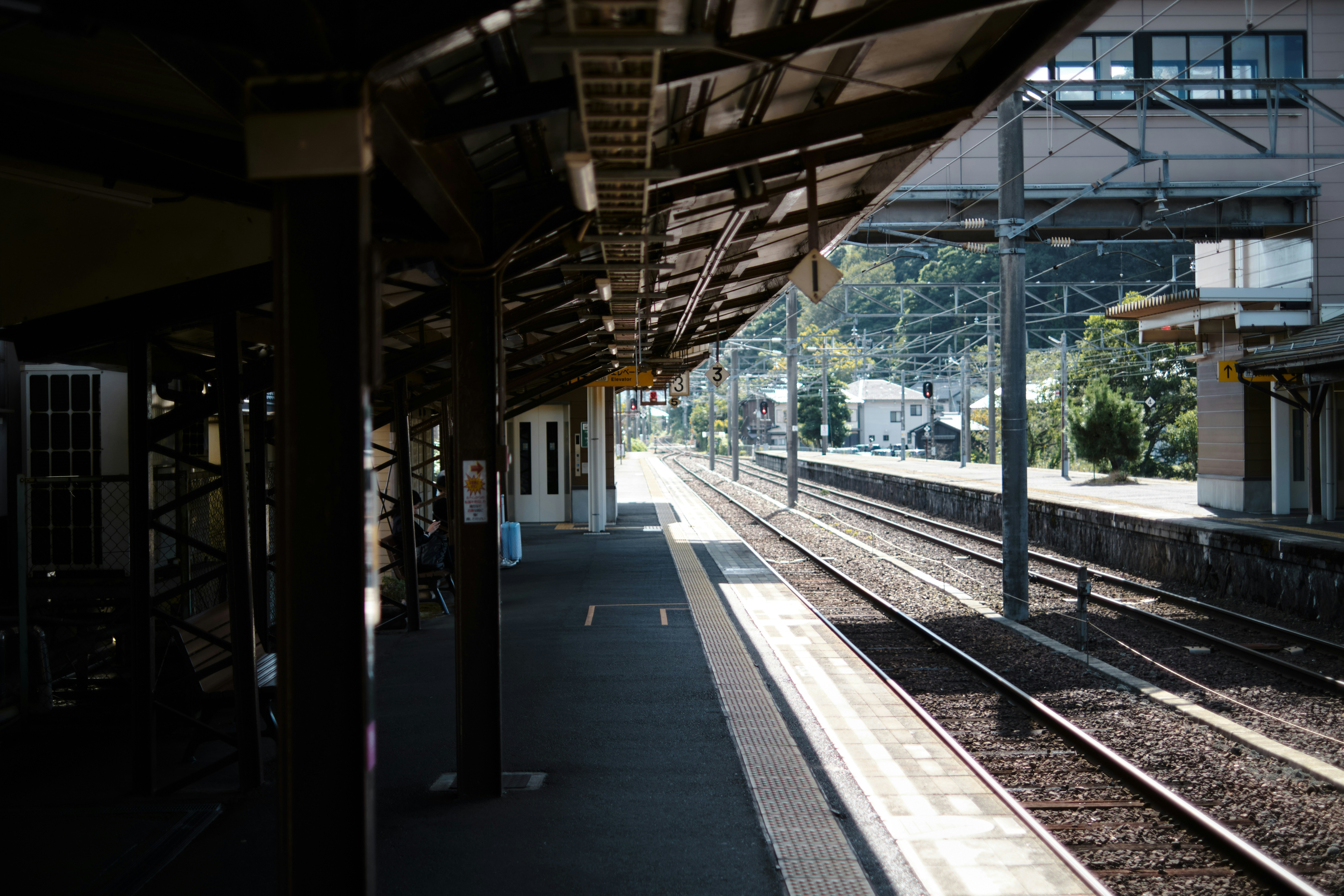 Empty train platform basking in sunlight with tracks leading into the distance.