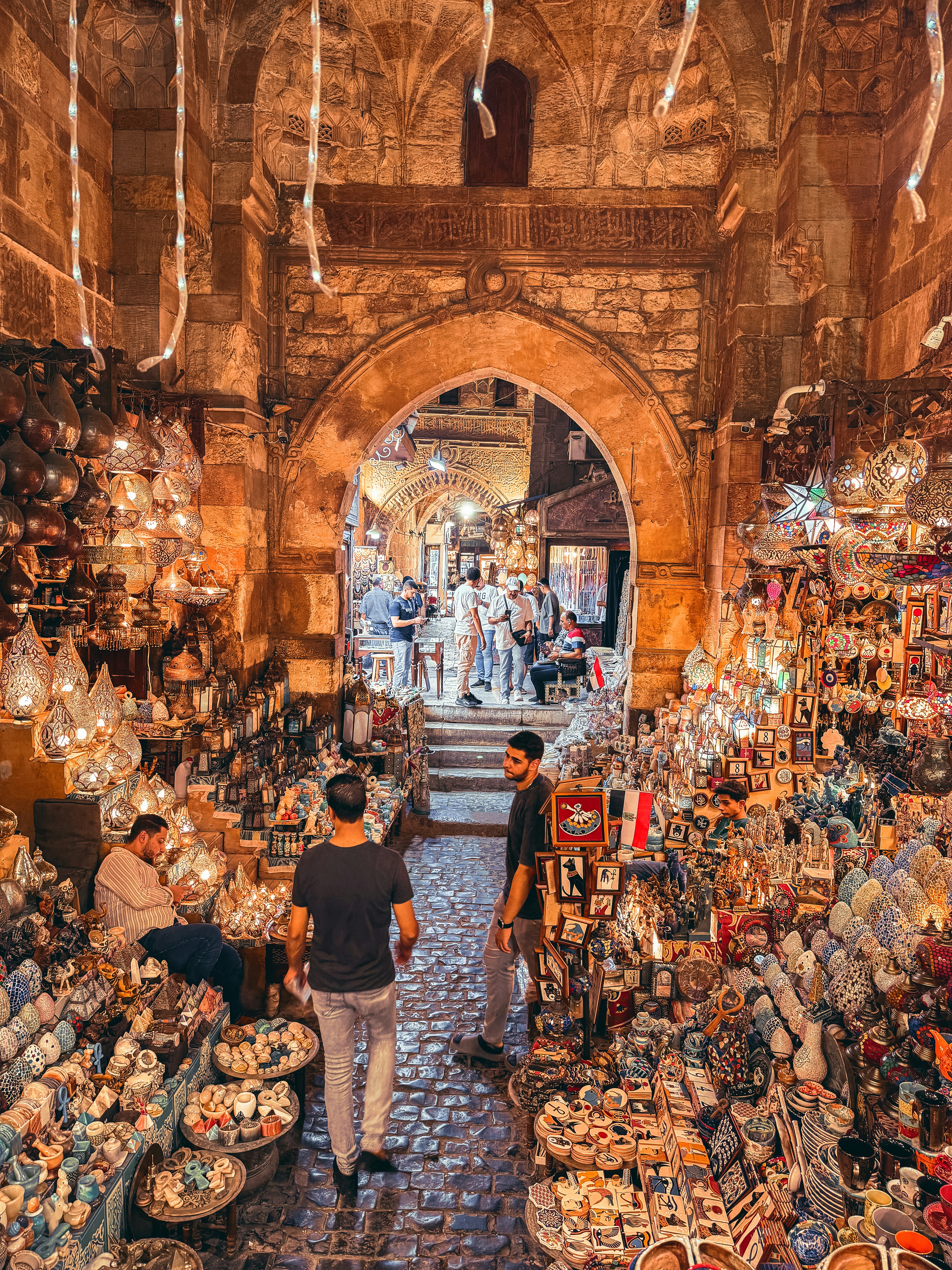 Foto Dua pria berjalan melalui pasar yang dipenuhi dengan banyak barang ...